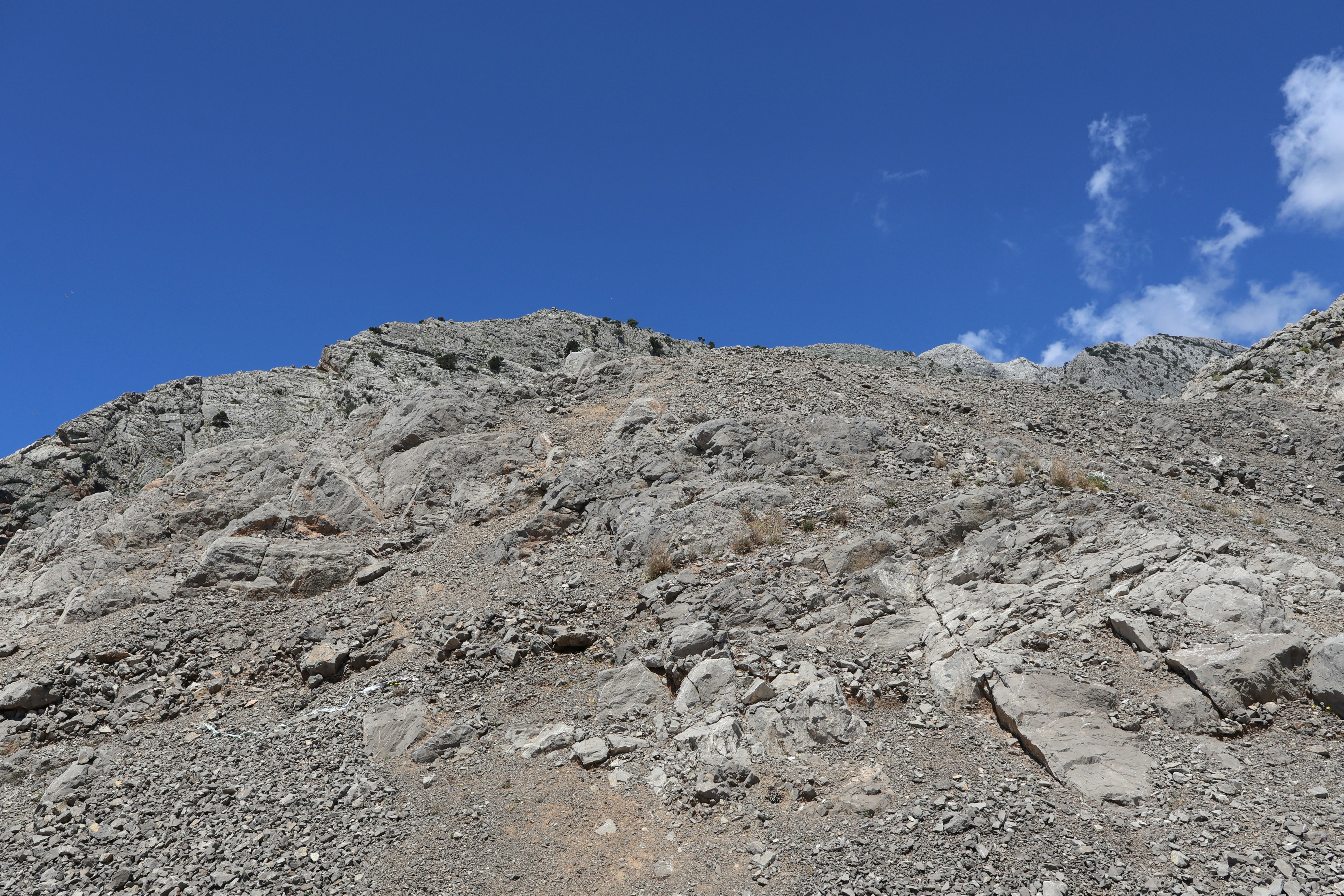 Rugged rocky mountain slope under a clear blue sky.