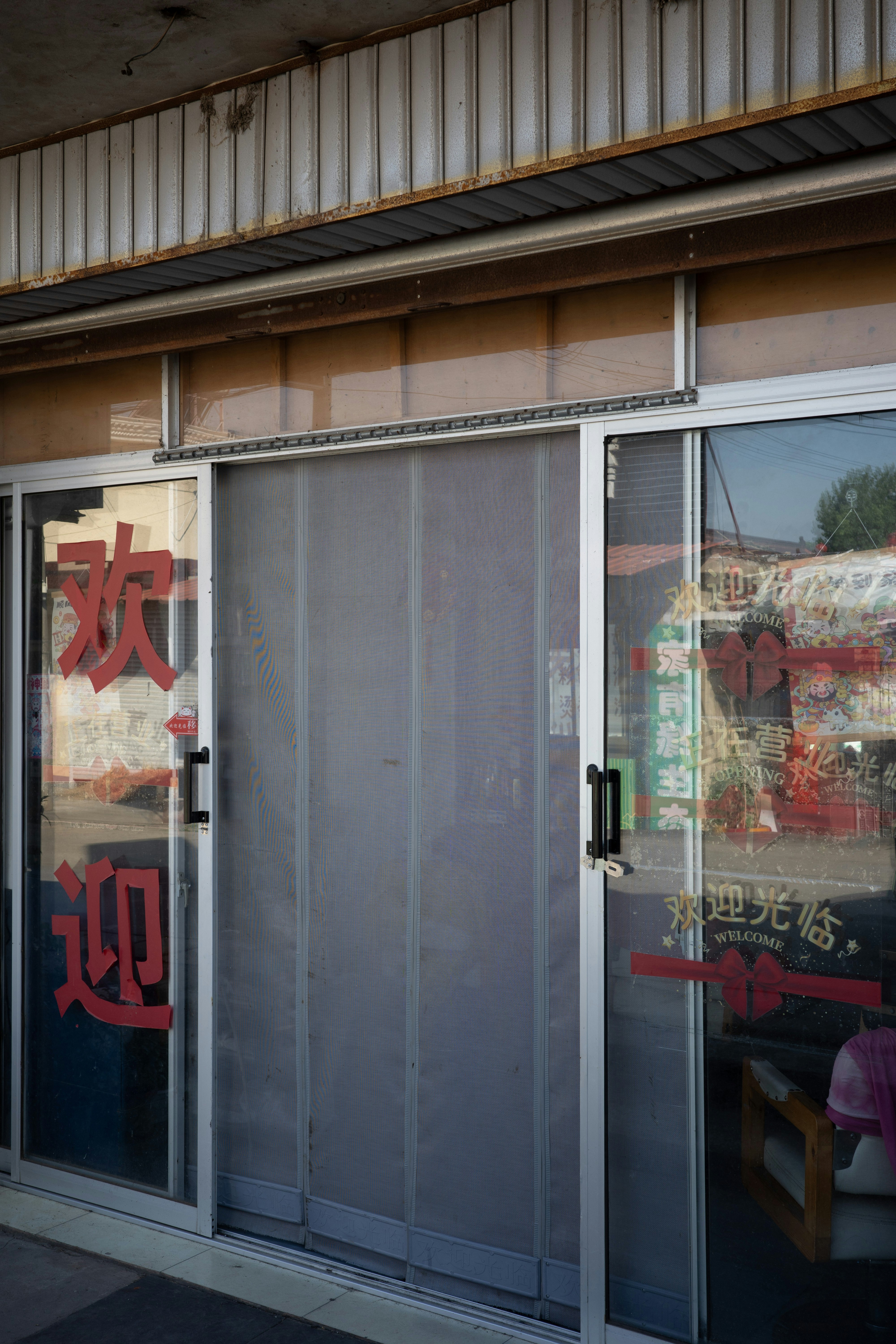 Chinese storefront glass doors with red calligraphy reflections