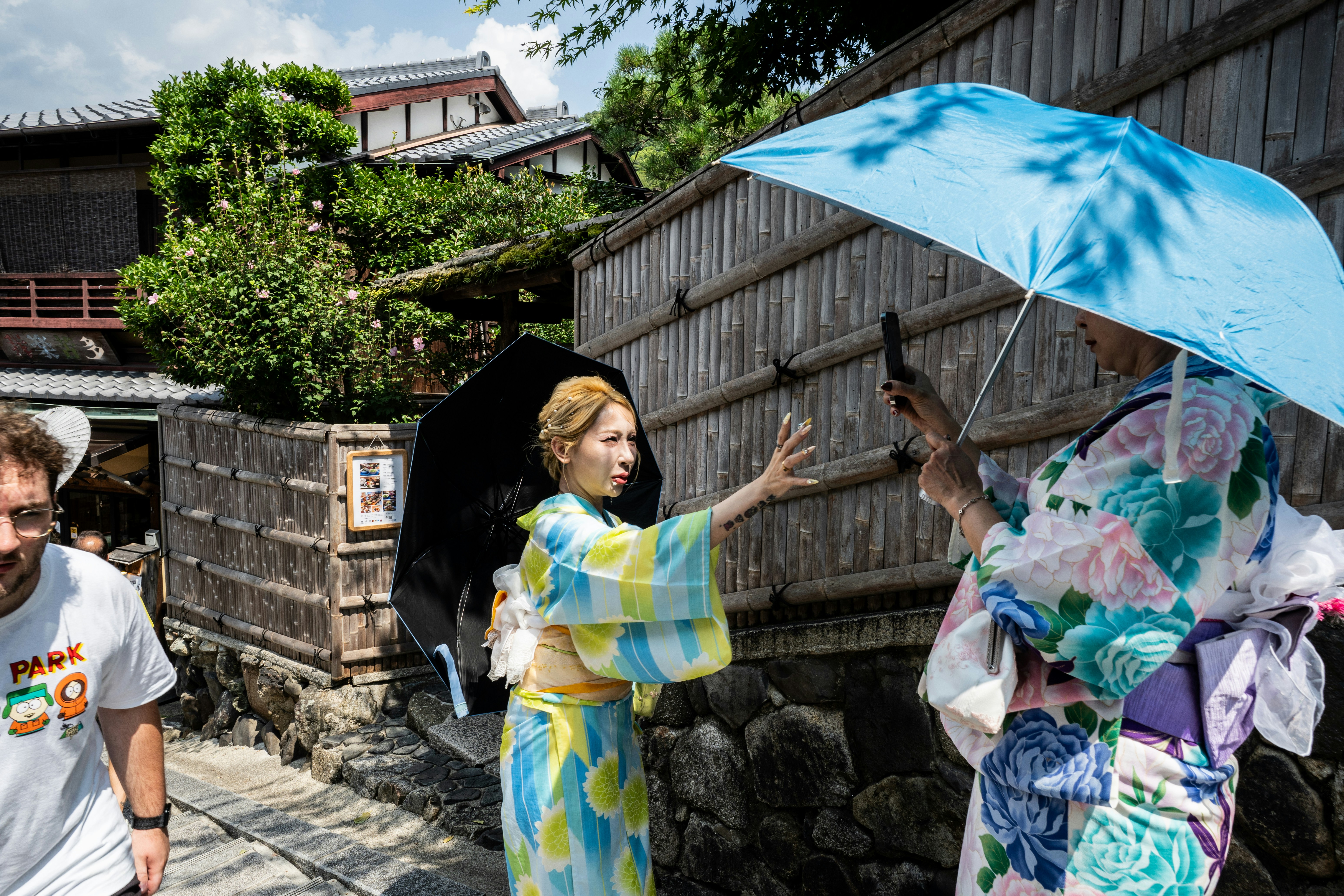 Two women in traditional kimonos posing with umbrellas outdoors.