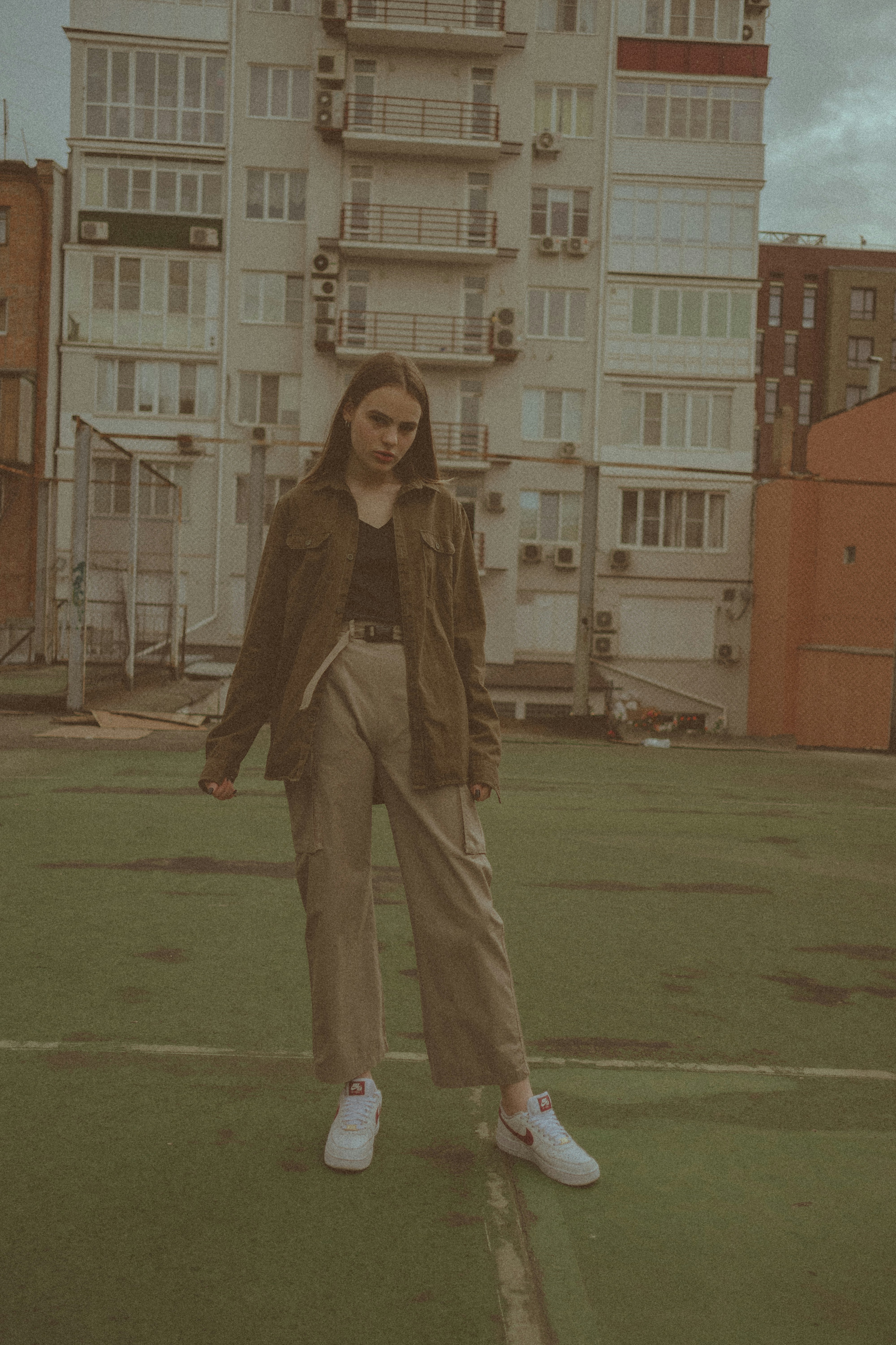 Urban Quiet: A girl in a brown jacket walking across a dim playground