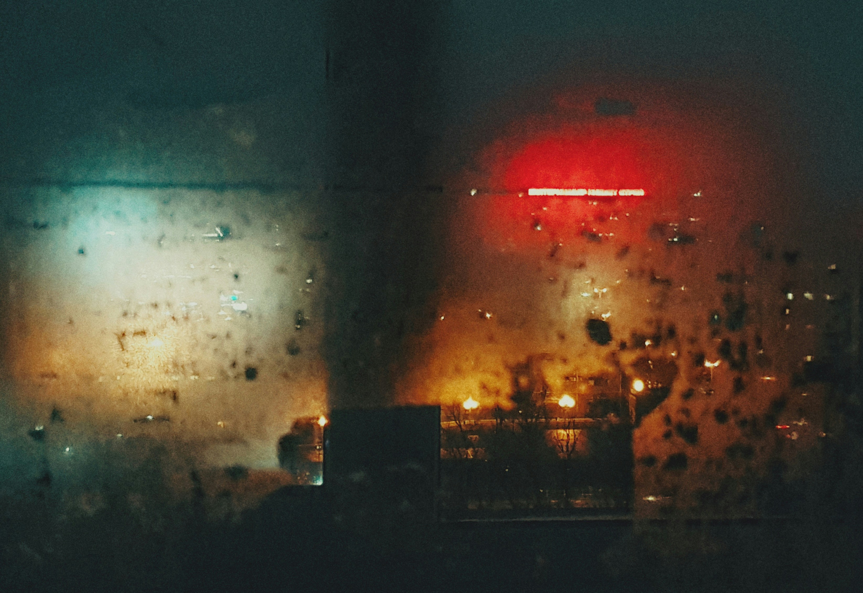 Blurry city lights through a wet window at night.