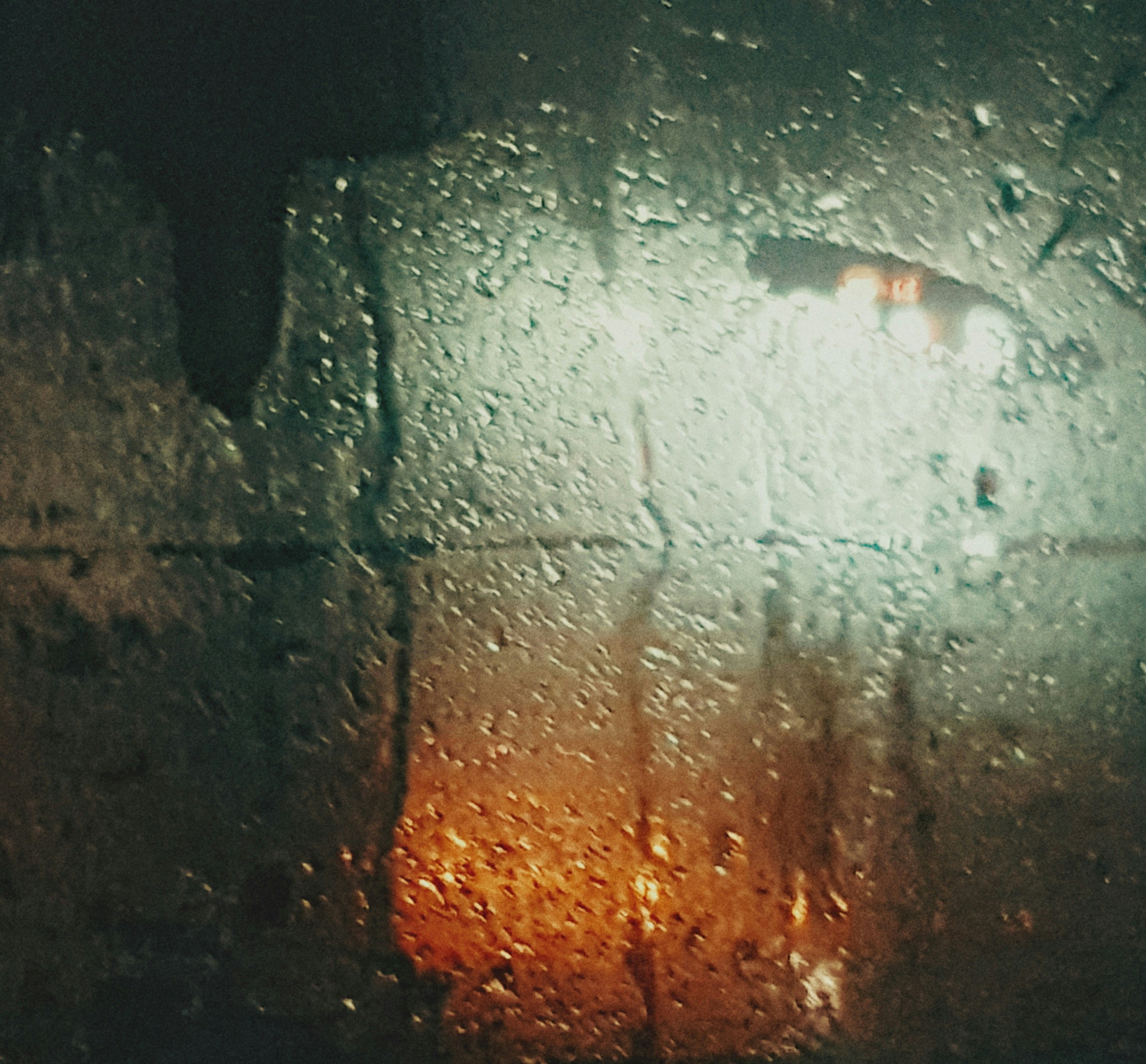 Wet asphalt reflecting bright and orange lights at night.