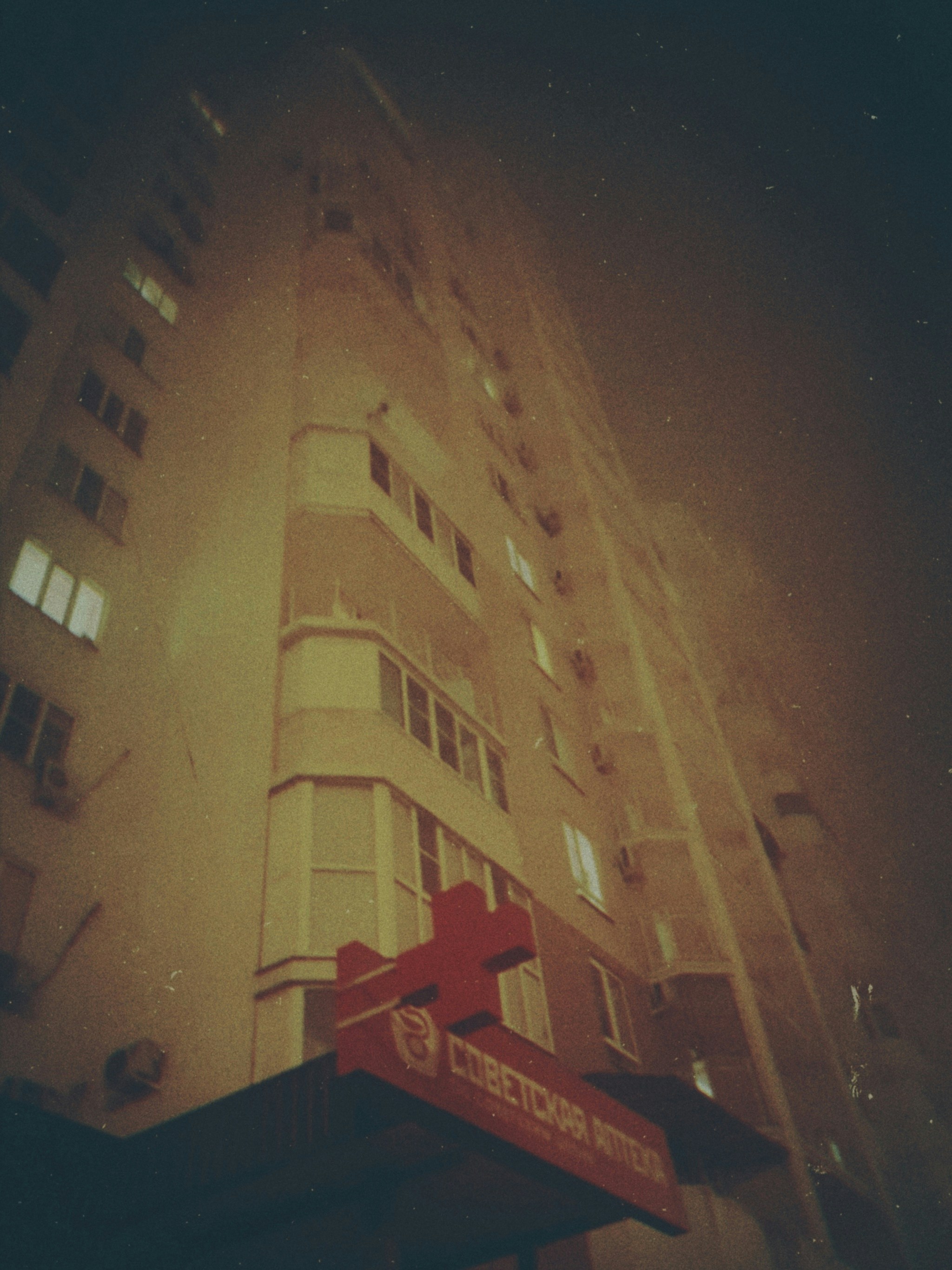 Night-Glow on a Dim Morning: A Corner Store Beneath a Towering Residenc