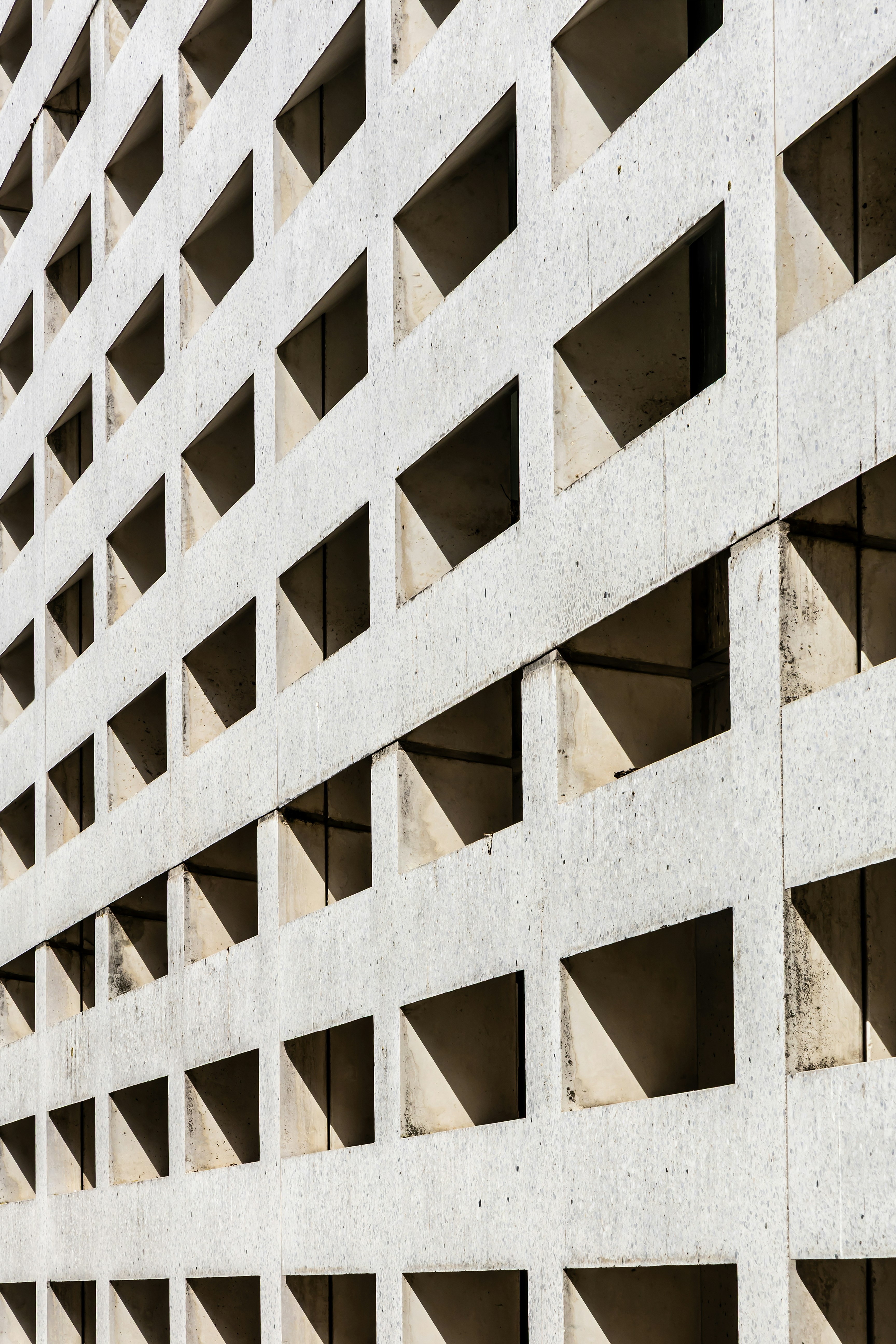 Concrete wall with square openings creating a pattern of shadows.