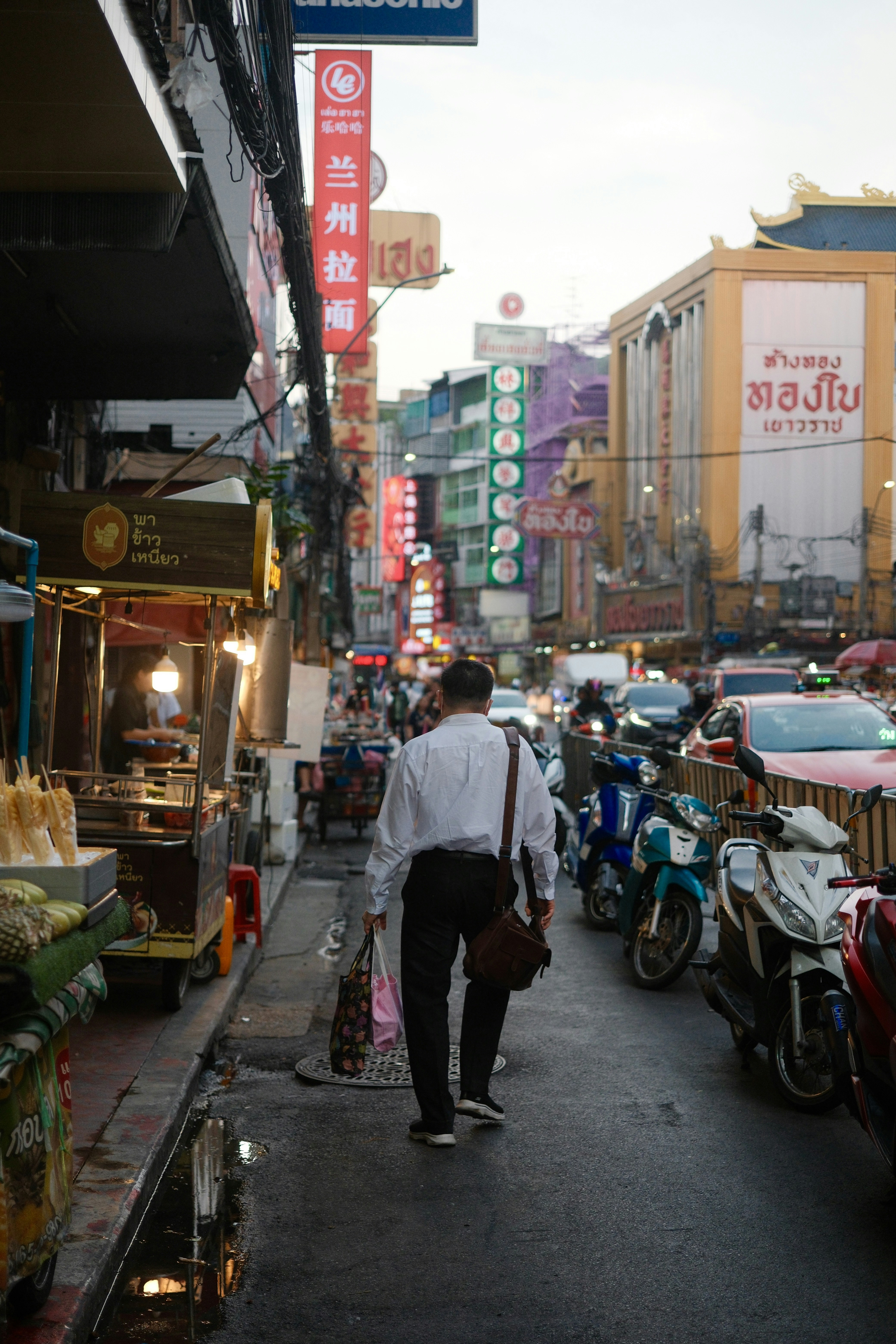 Street stride: a commuter with a brown bag among neon signs and scooters