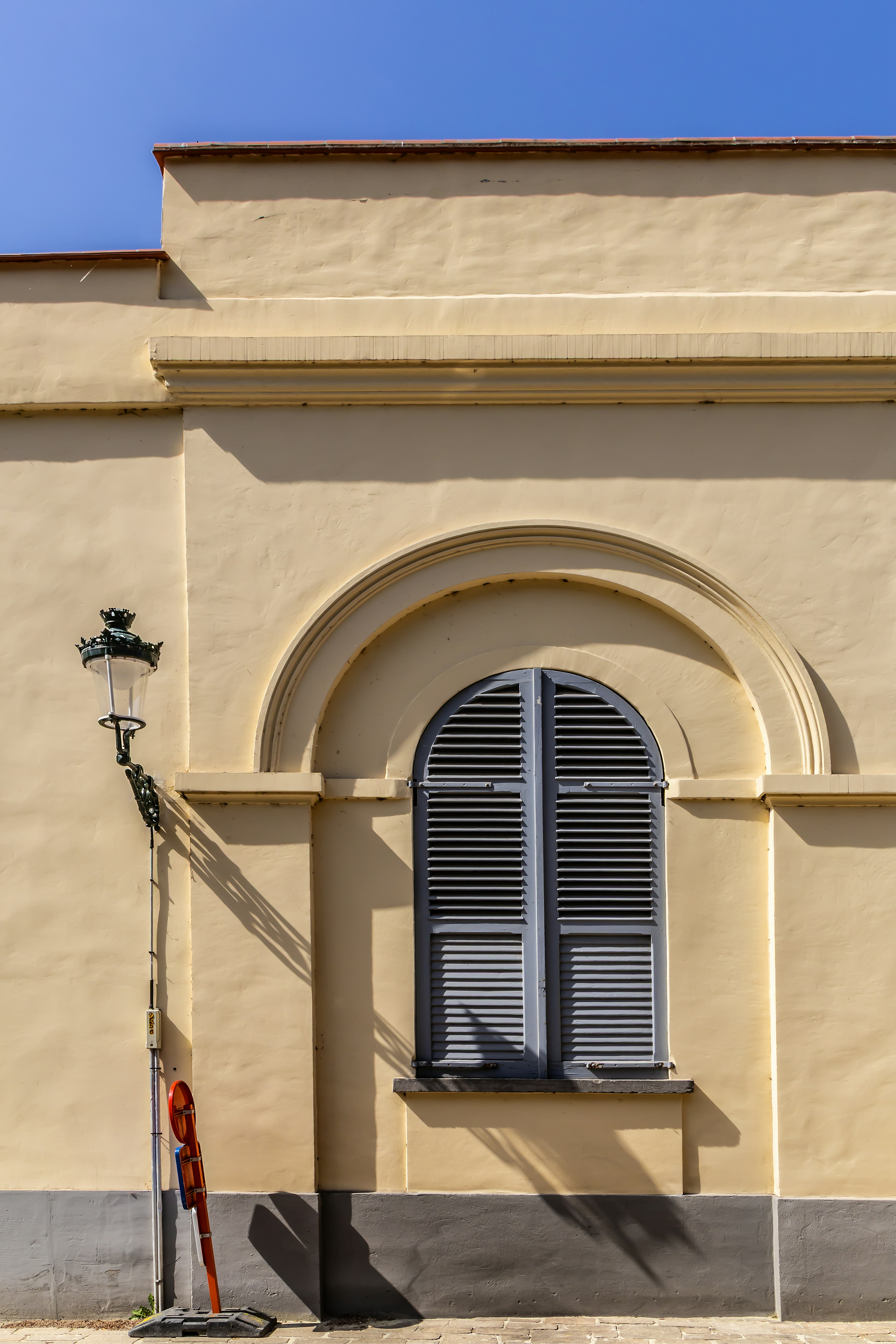 Beige Facade with Arched Window and Vintage Streetlamp