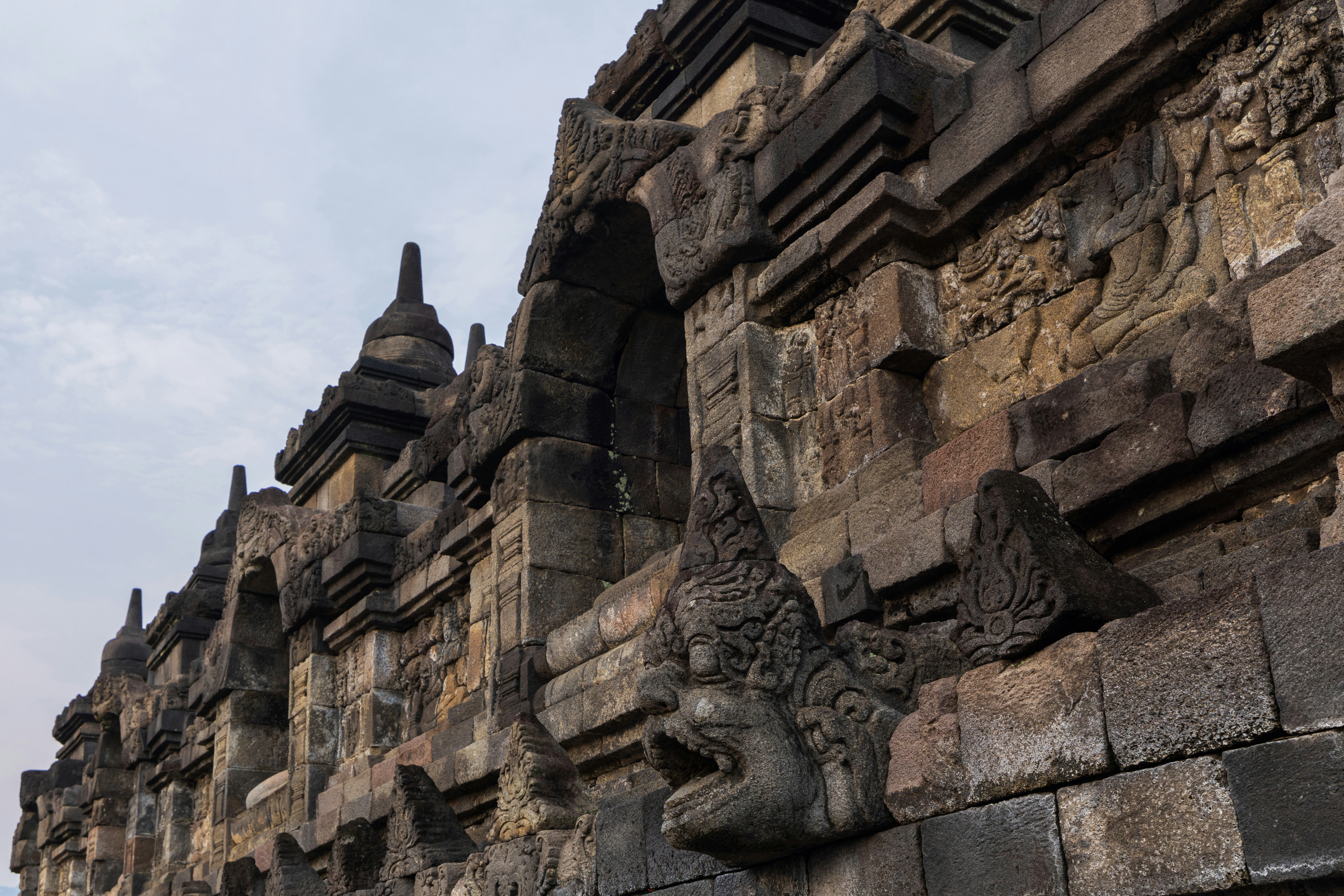 Ancient stone temple with intricate carvings under a cloudy sky.