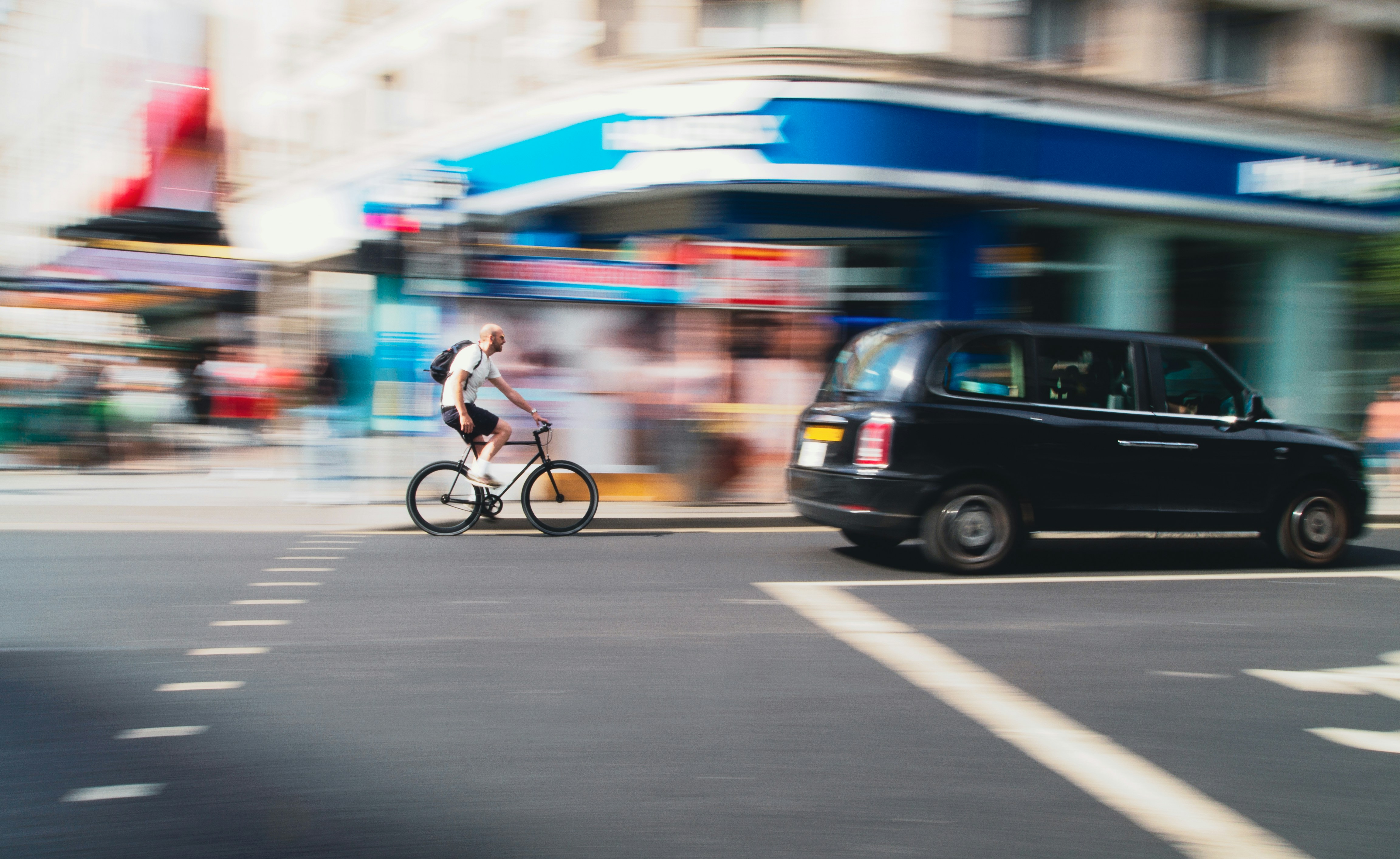 Blurred City Cyclist in Motion Across a Busy Street