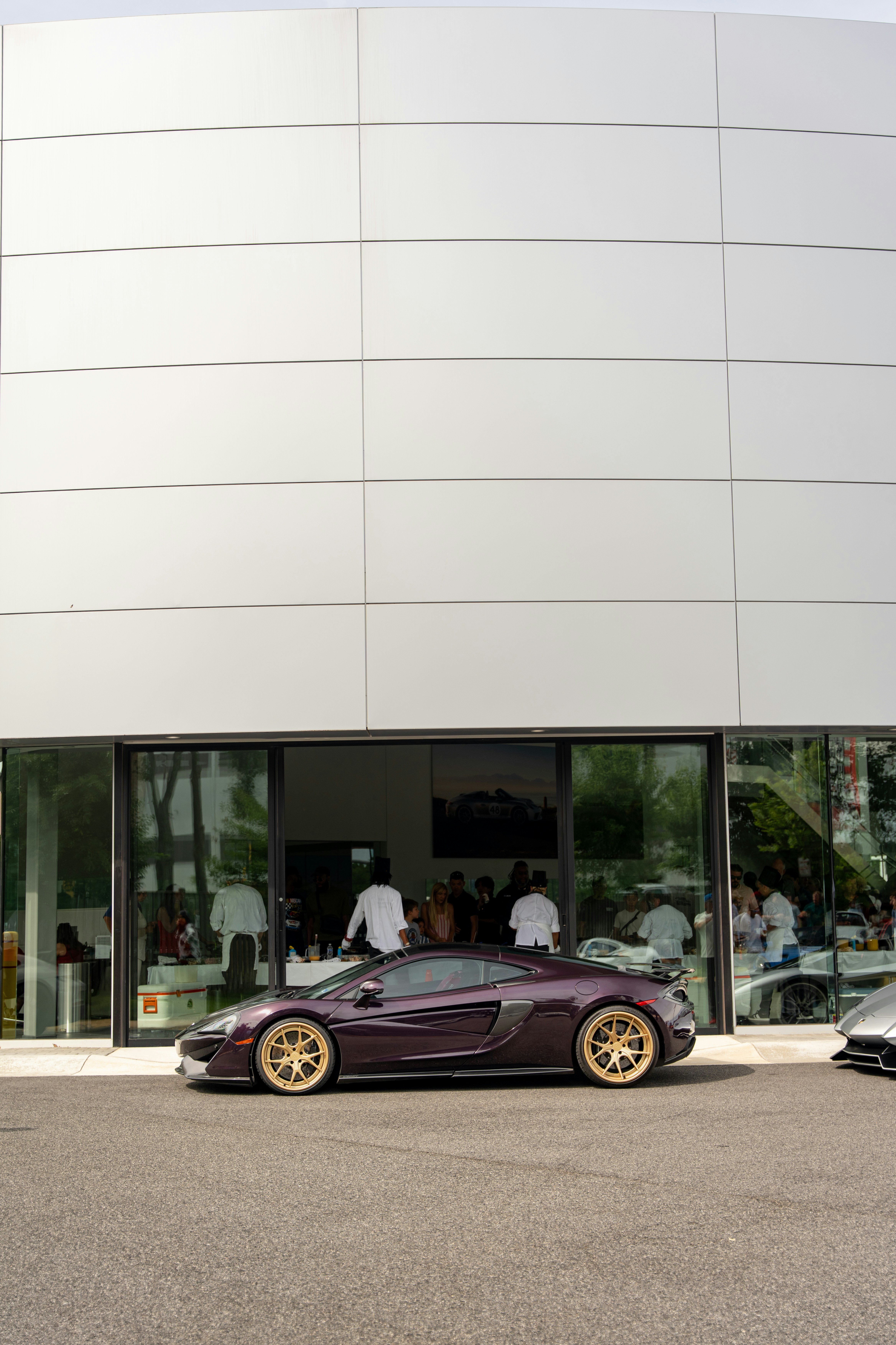 Low-Slung Beauty: Burgundy Sports Car Quietly Anchors a Modern showroom