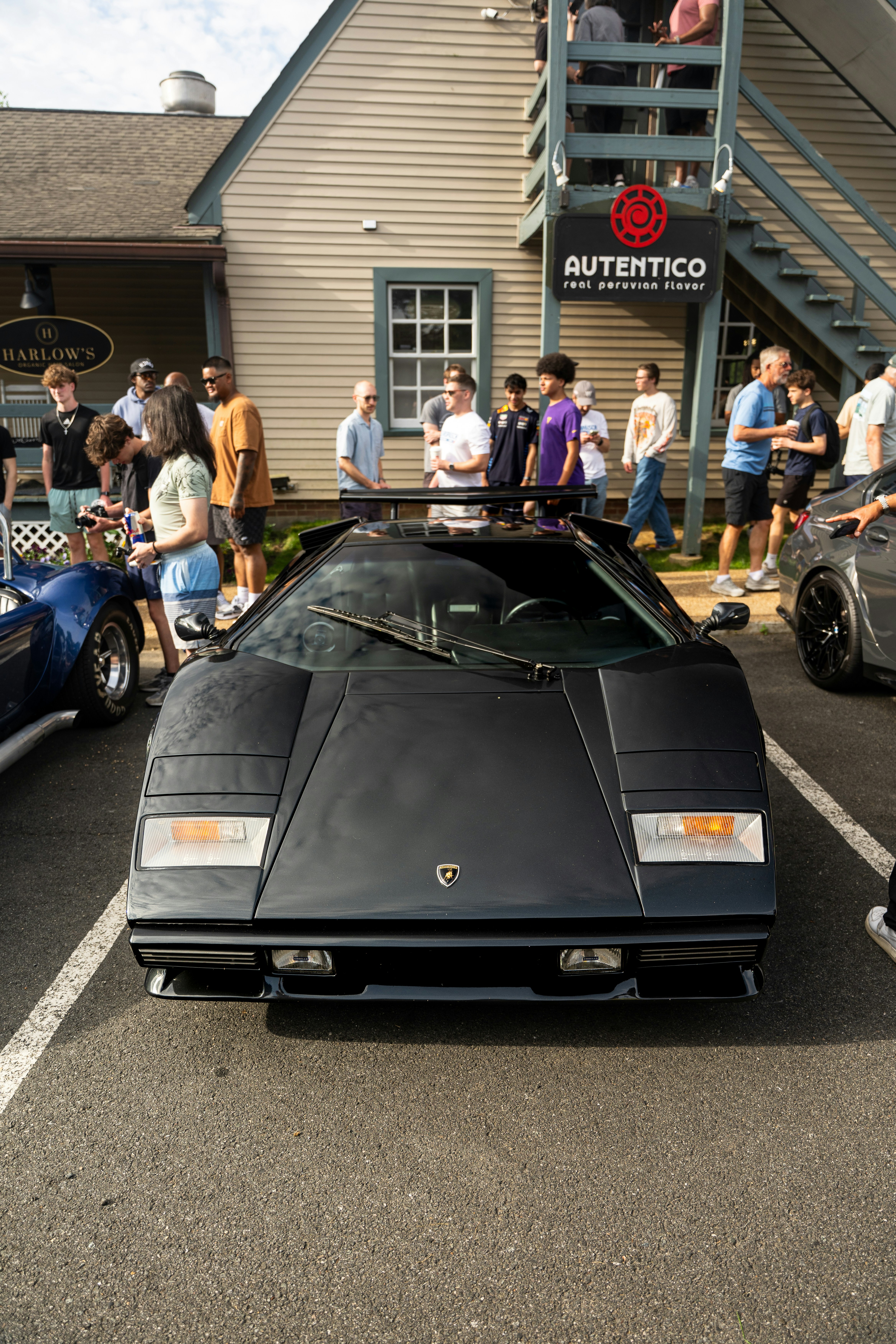 A black lamborghini countach parked at an outdoor car show.