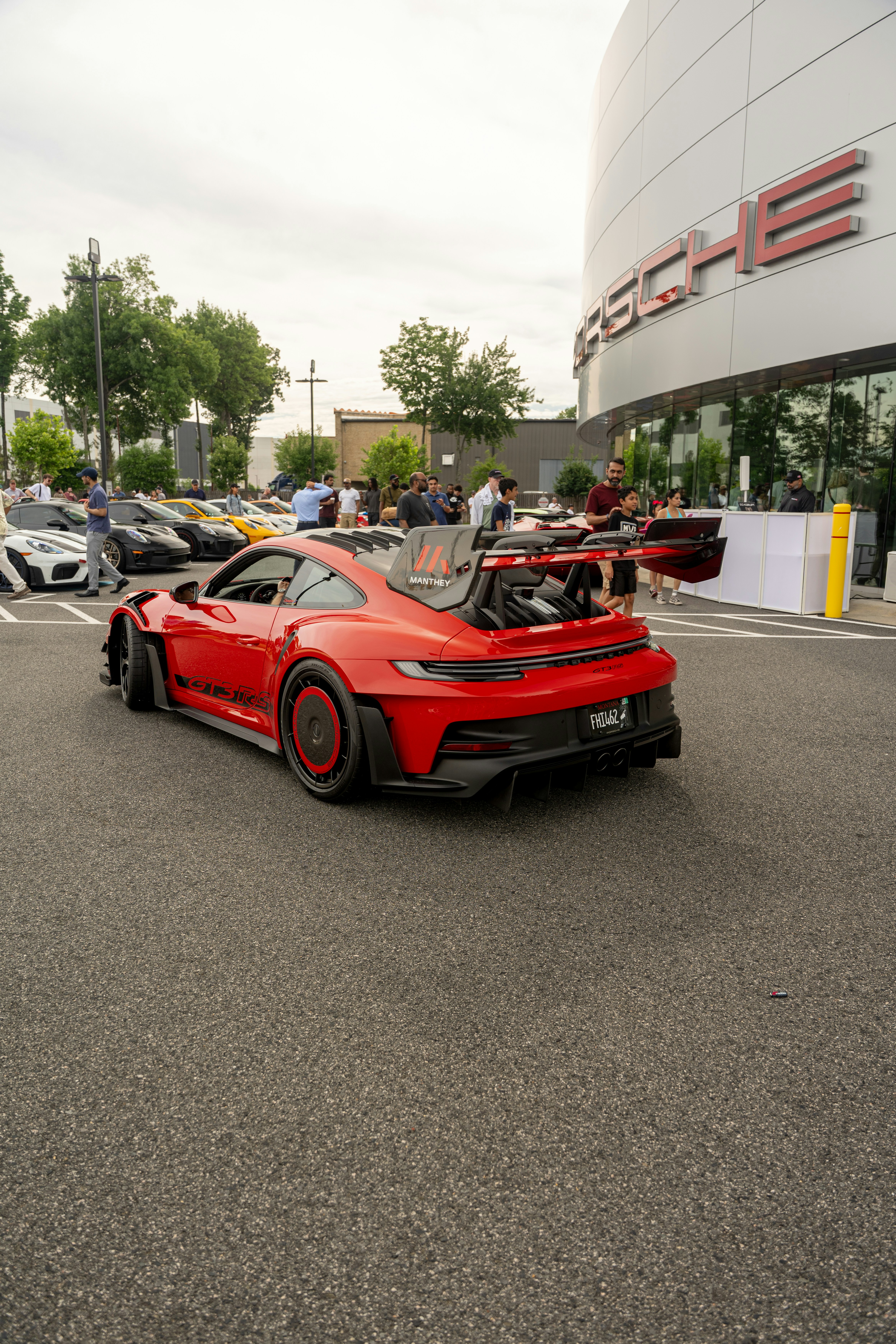 Red porsche 911 gt3 rs parked near a porsche dealership.