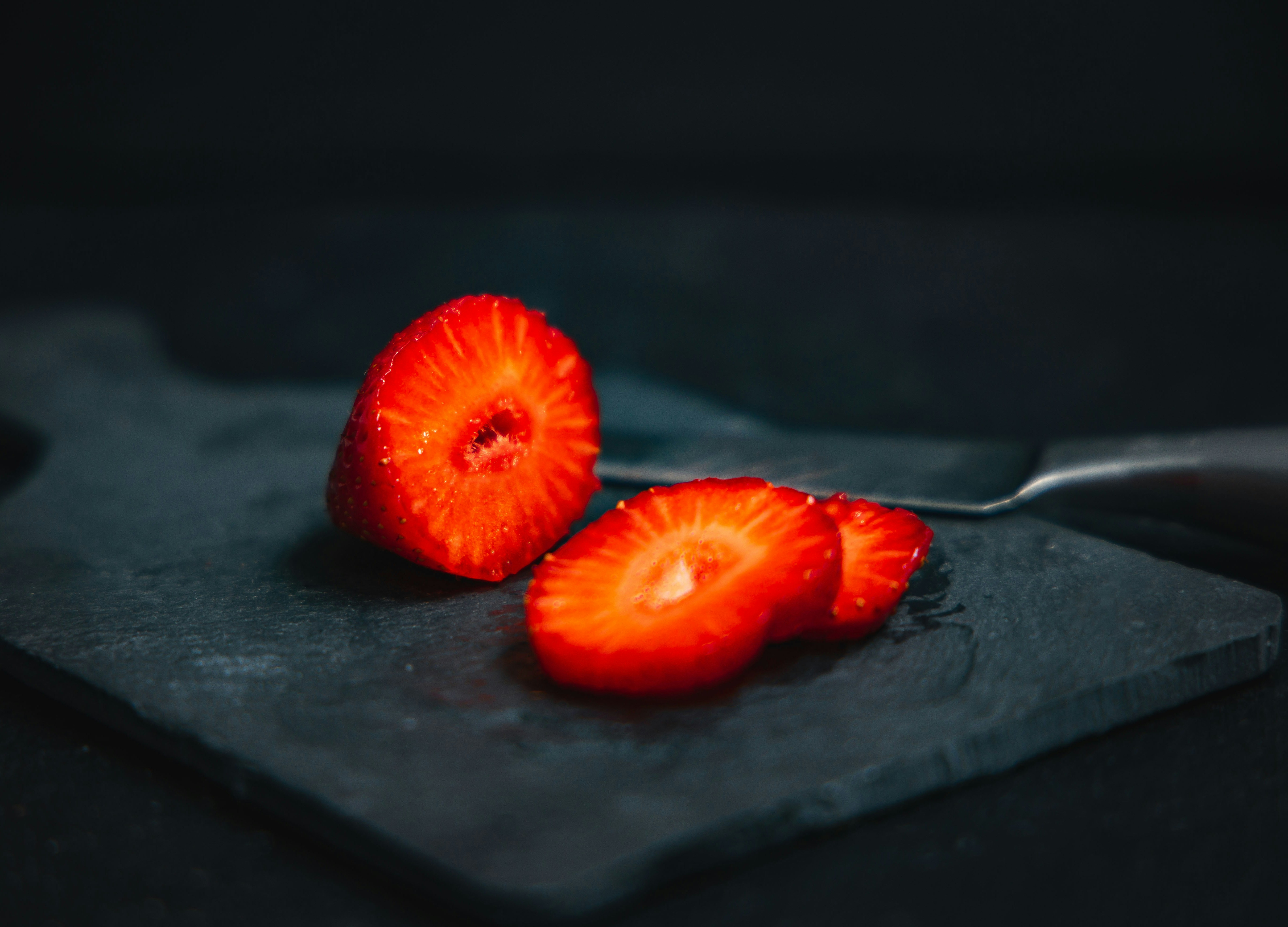 Red Contrast on Slate: A Halved Strawberry on a Dark Board