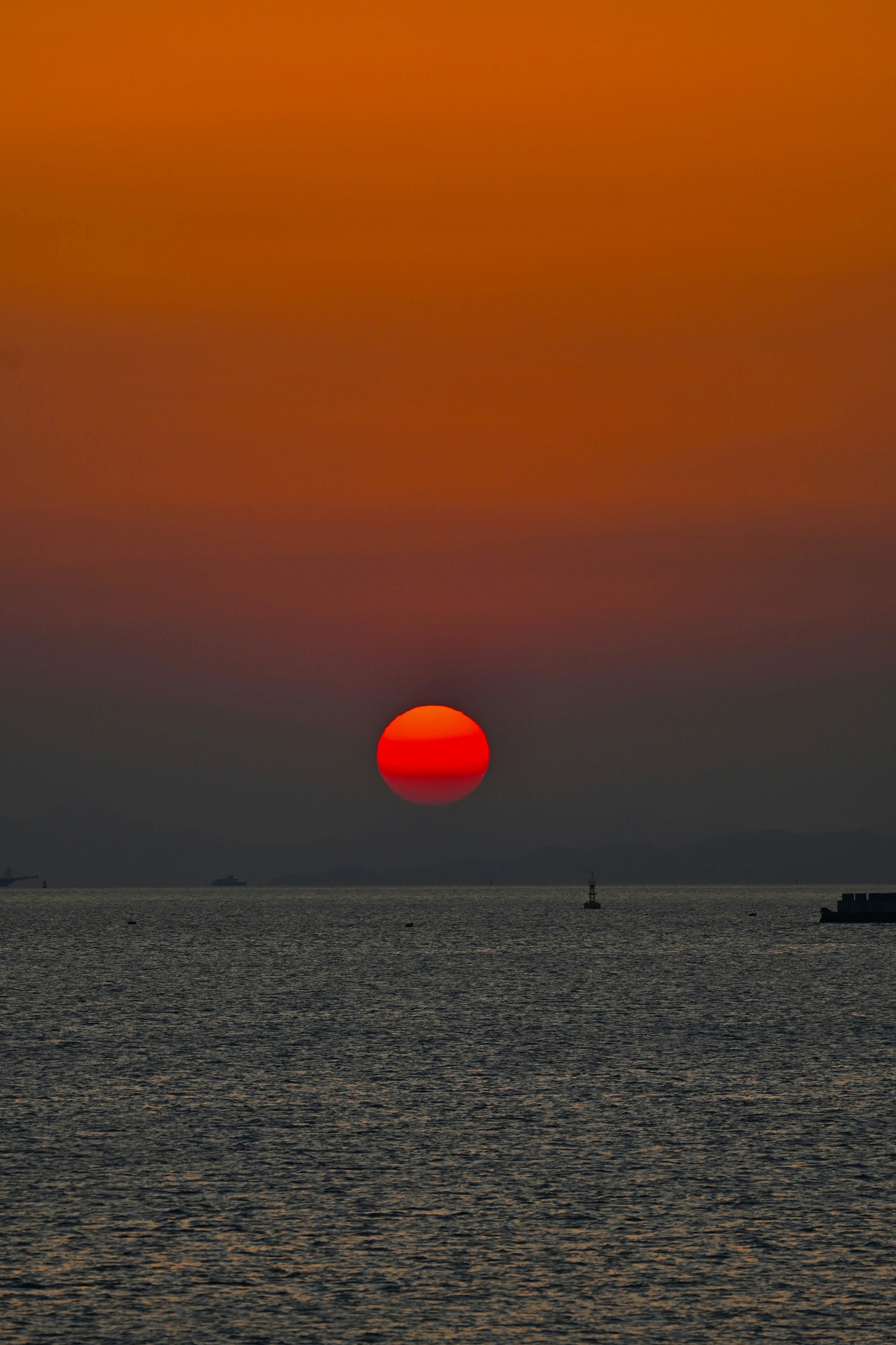 Red Sphere on the Horizon: A Quiet Sunset Over Calm Seas