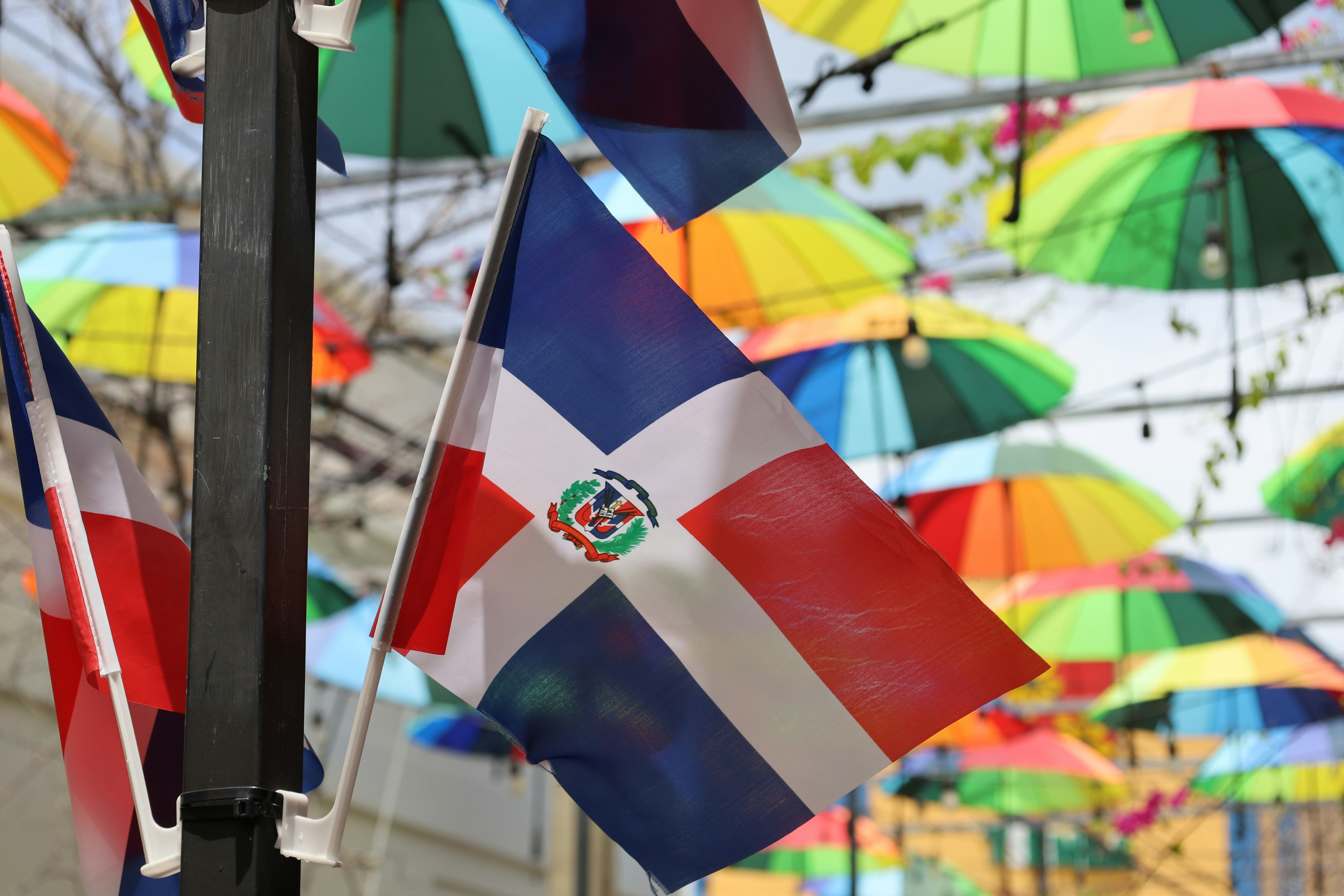 Colorful Umbrella Mosaic Framing Dominated by Dominican Flag Amid Street Festivity