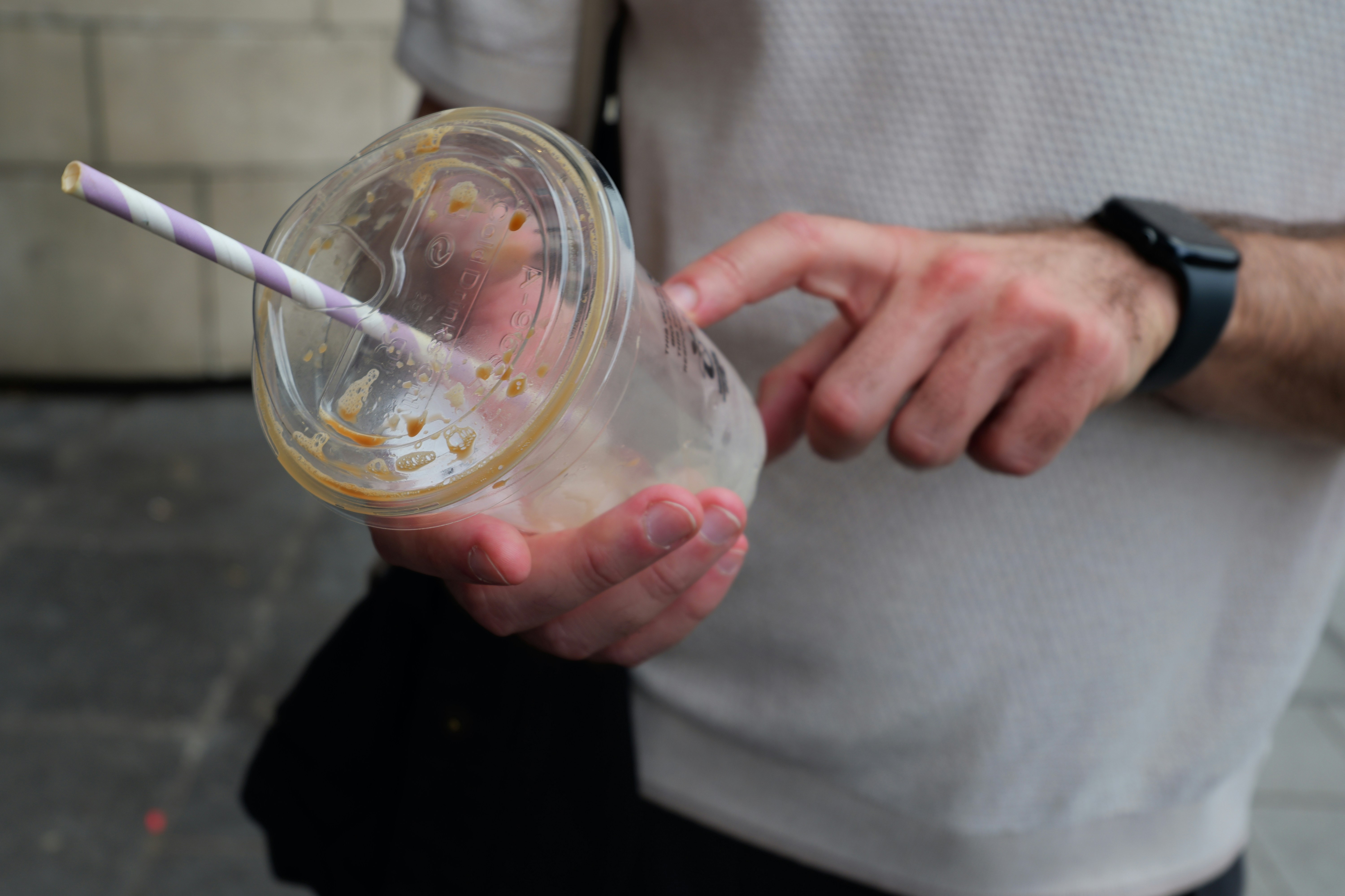 A person holds an empty glass with a straw.
