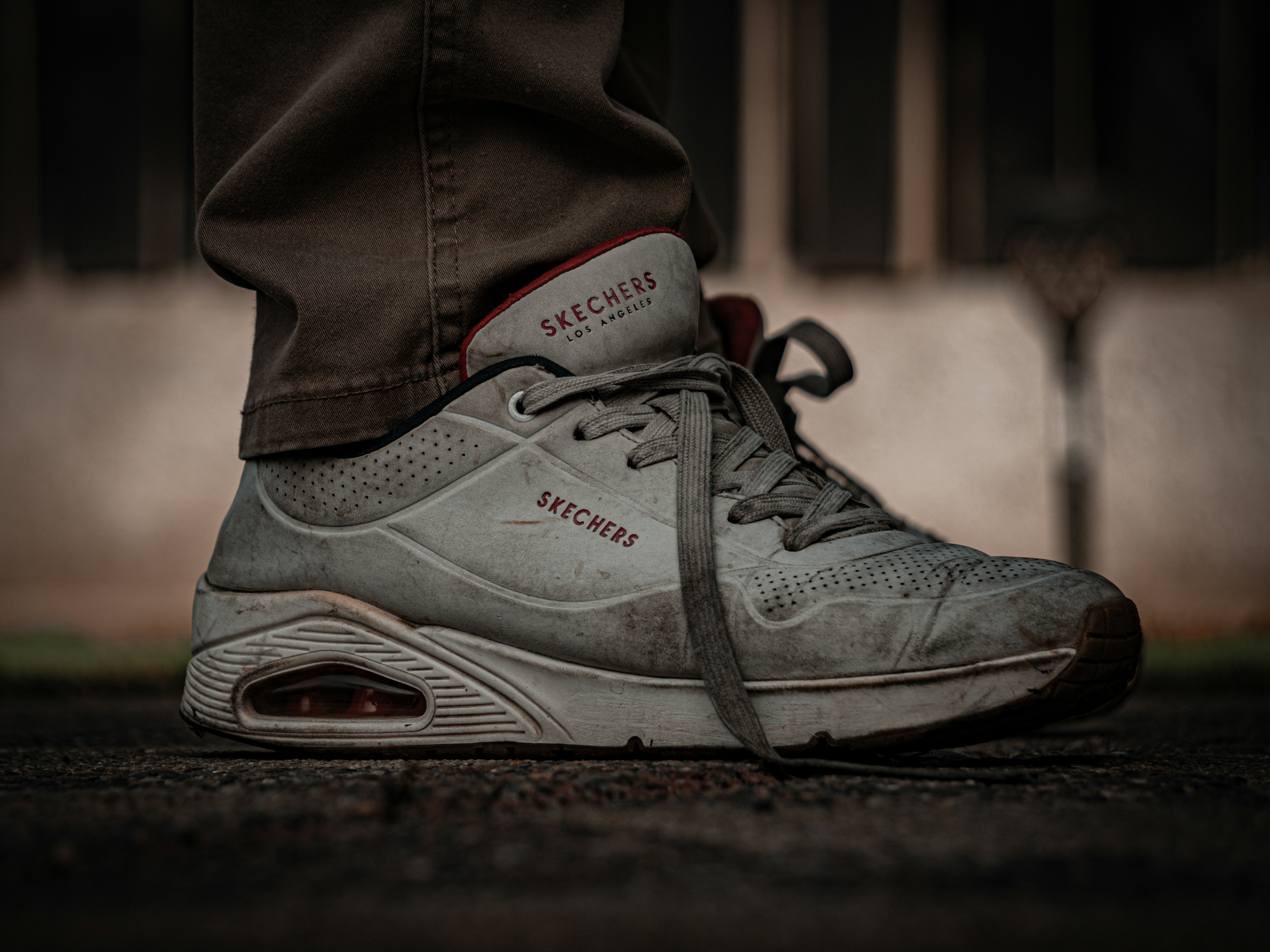 A person's foot wearing a dirty white skechers shoe.