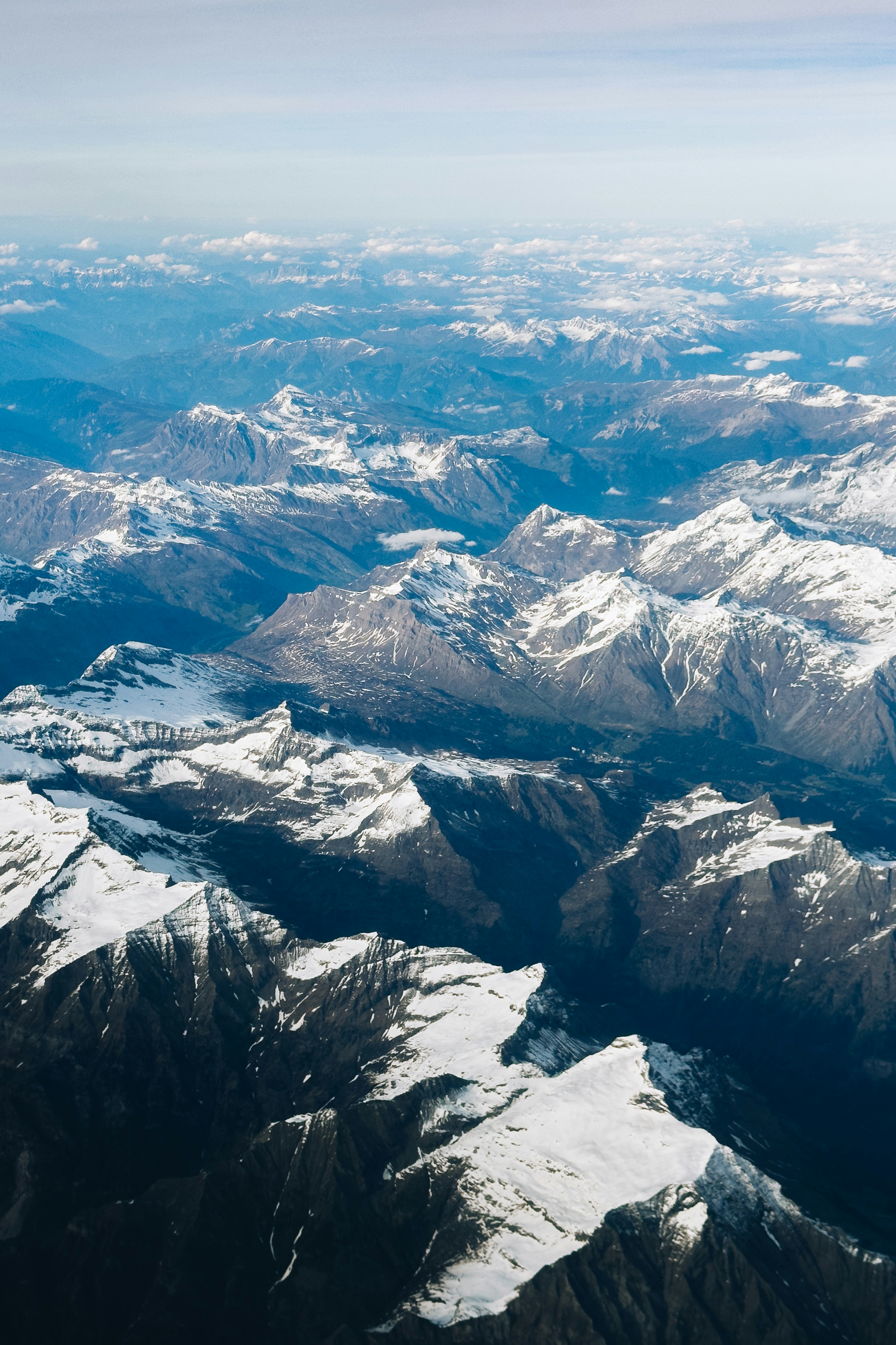 Aerial view of vast snow-capped mountains under a clear sky.