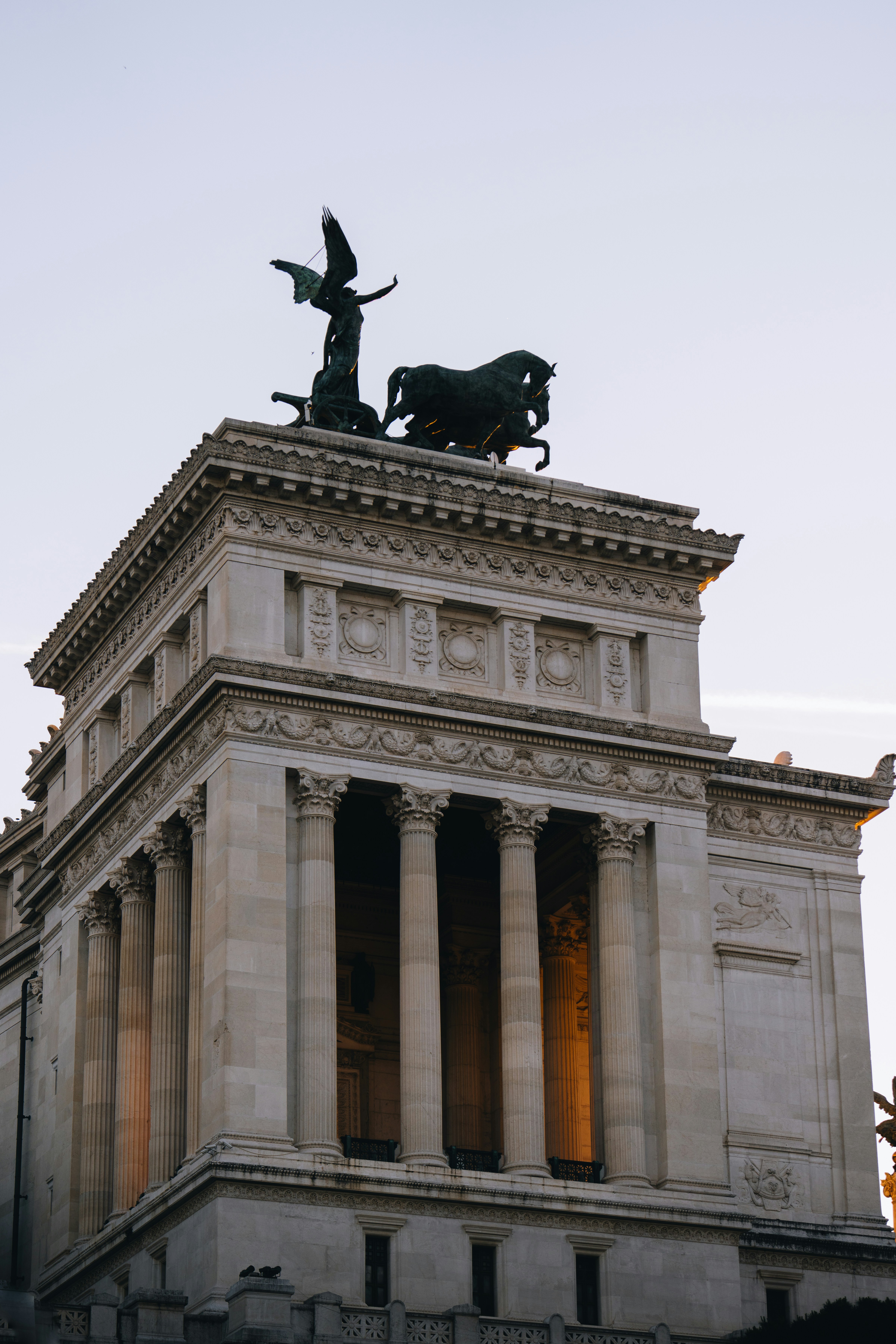 Grand classical monument with bronze statues under a clear sky.