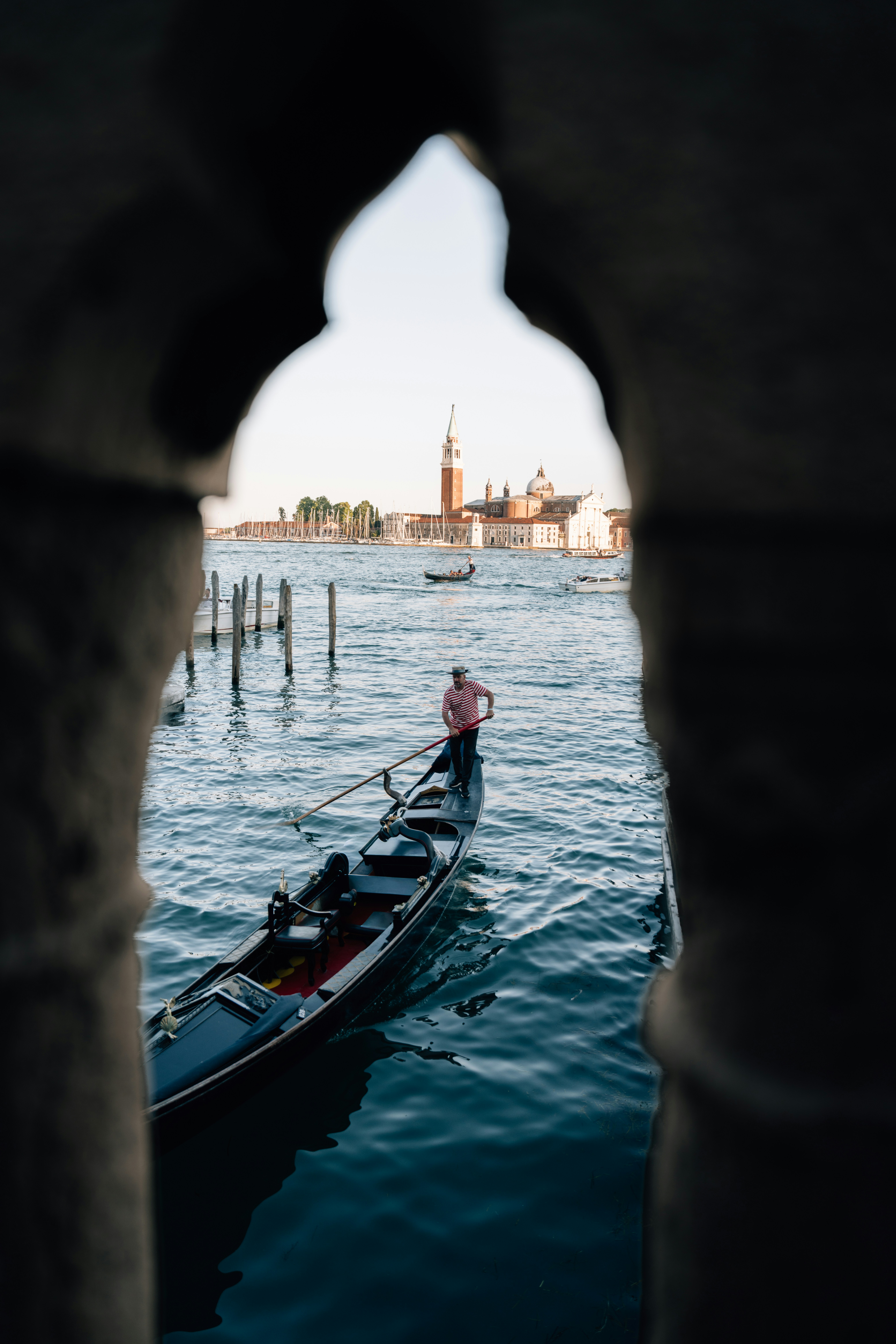 Gondola on venetian canal framed by stone archway.