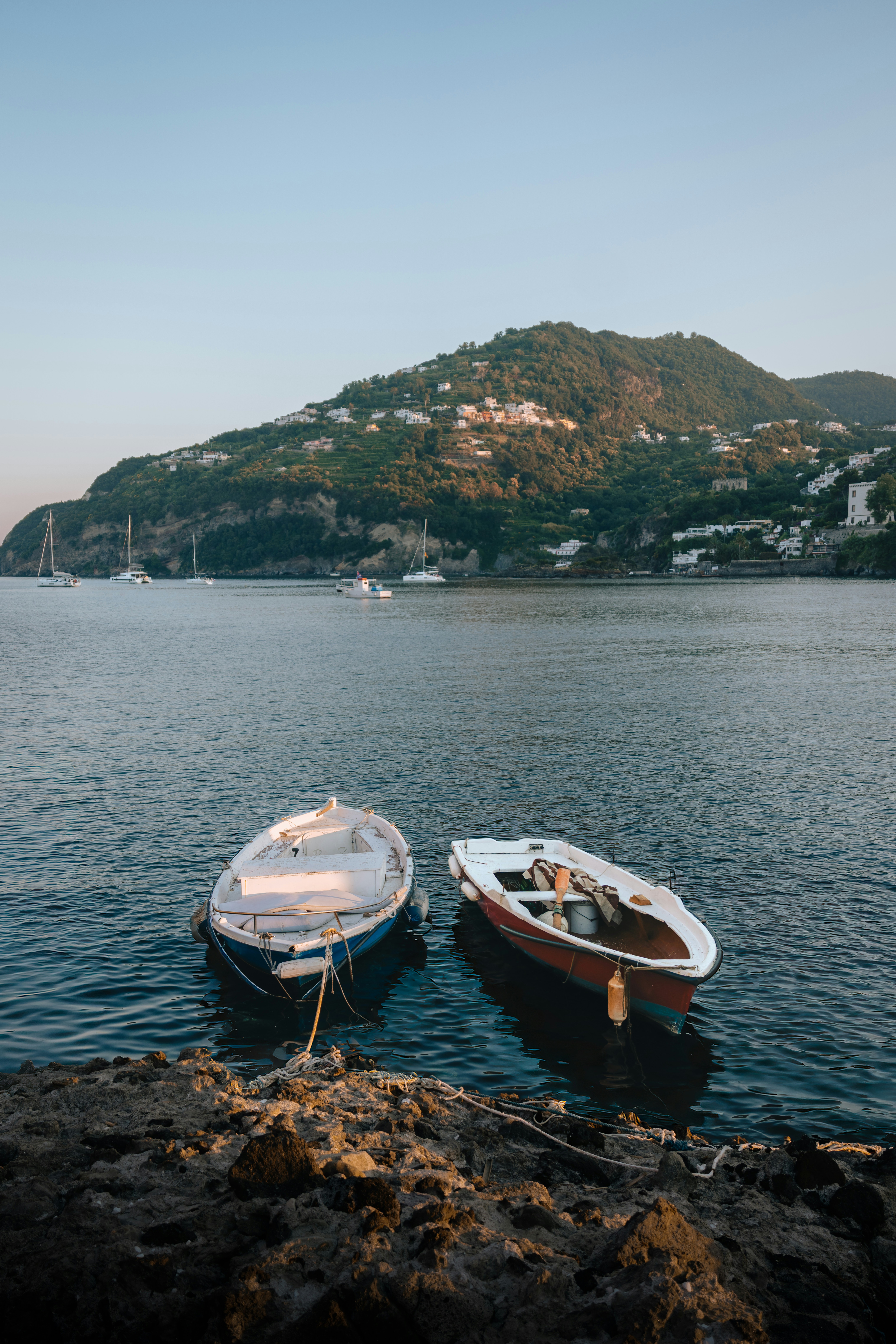 Two Boats at the Edge of a Quiet Harbor with a Hillside Village