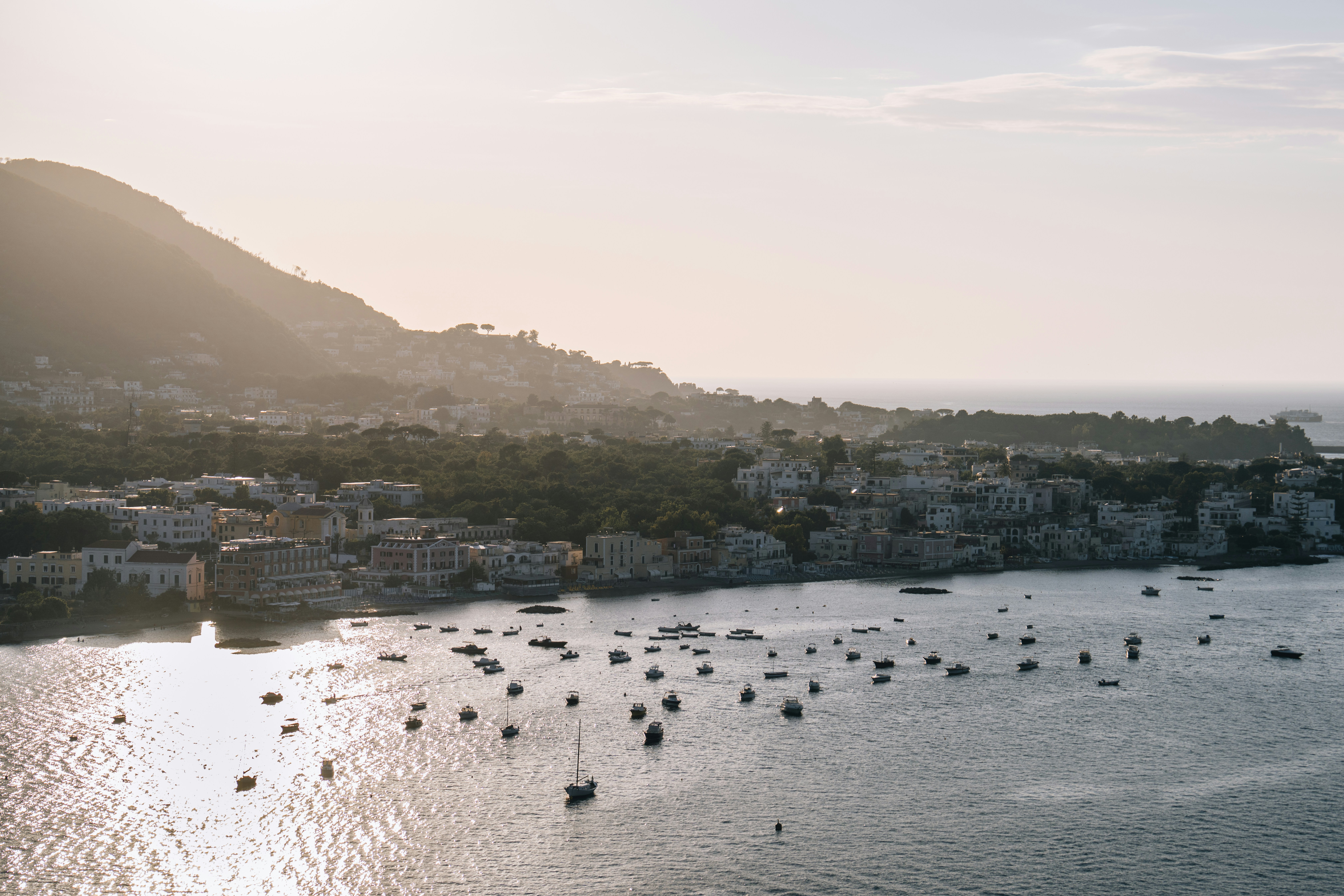 Coastal town and boats in a bay at sunset.