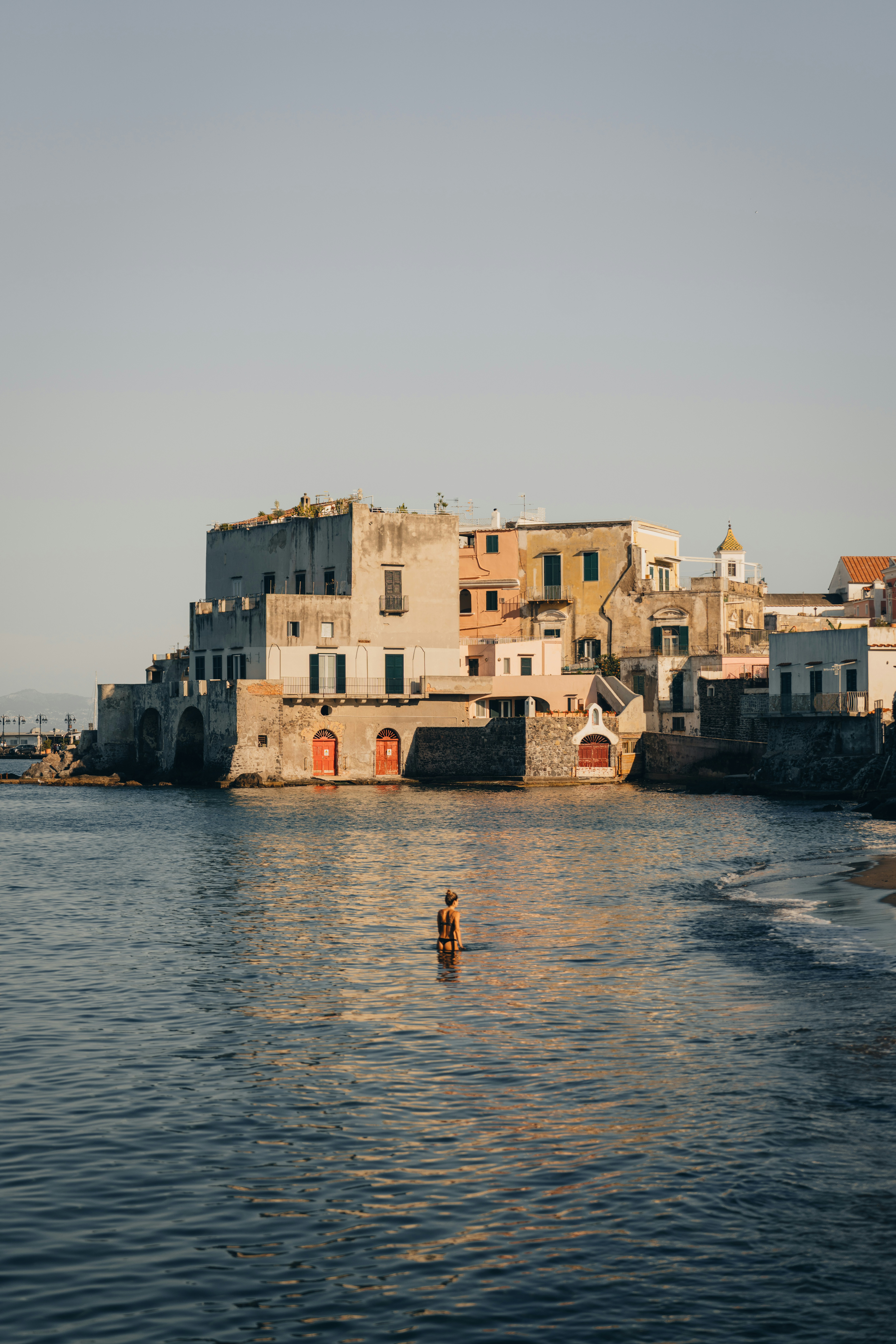 Harbored Village at Dusk: A Lone Surfer in Quiet Waters