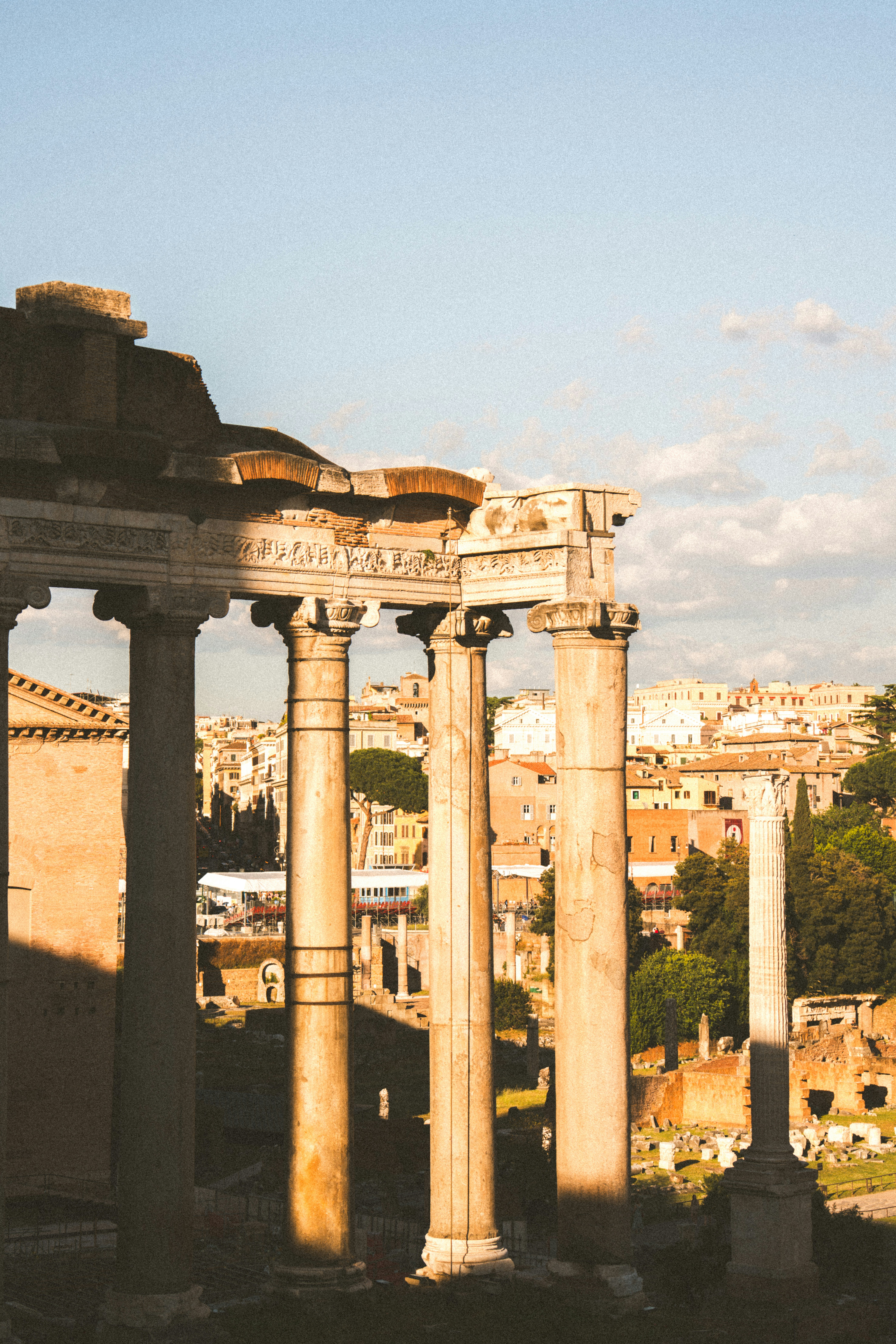 Ancient roman columns against a city skyline and blue sky.