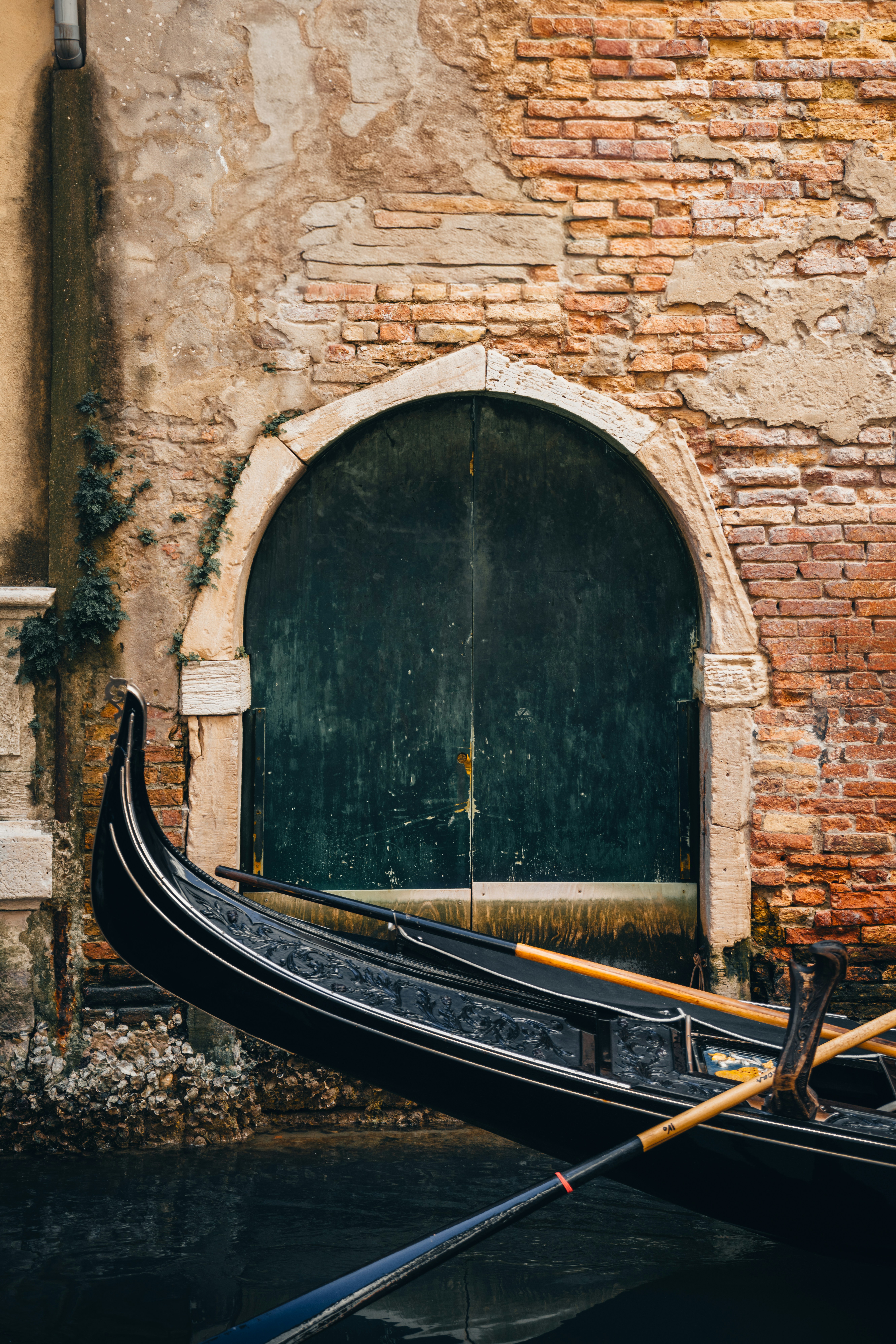 Gondola in a venice canal before an old brick doorway.