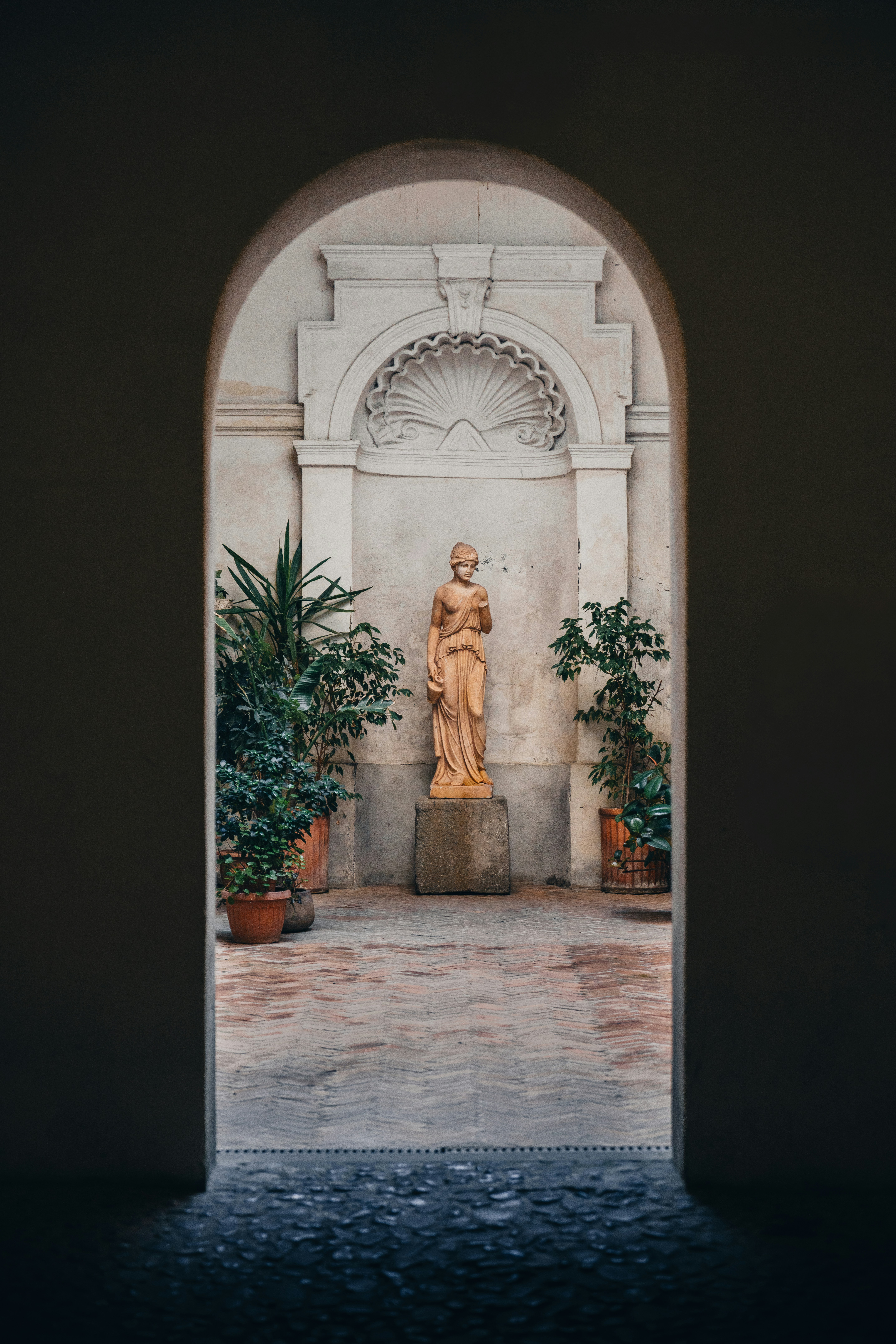 Archway Reverie: A Statue Framed by Garden Greens