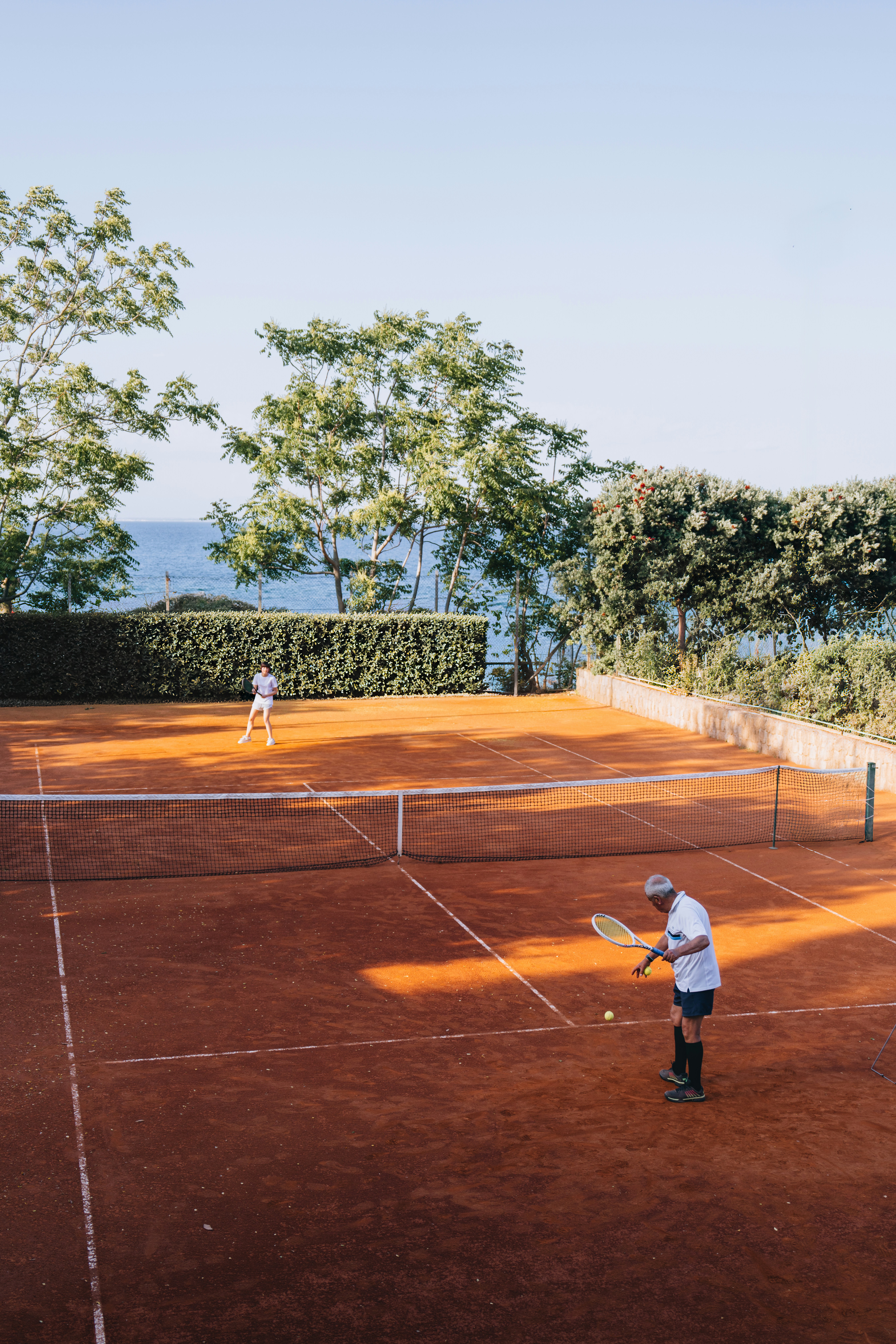 Sunlit Clay: A Quiet Tennis Duel by the Sea
