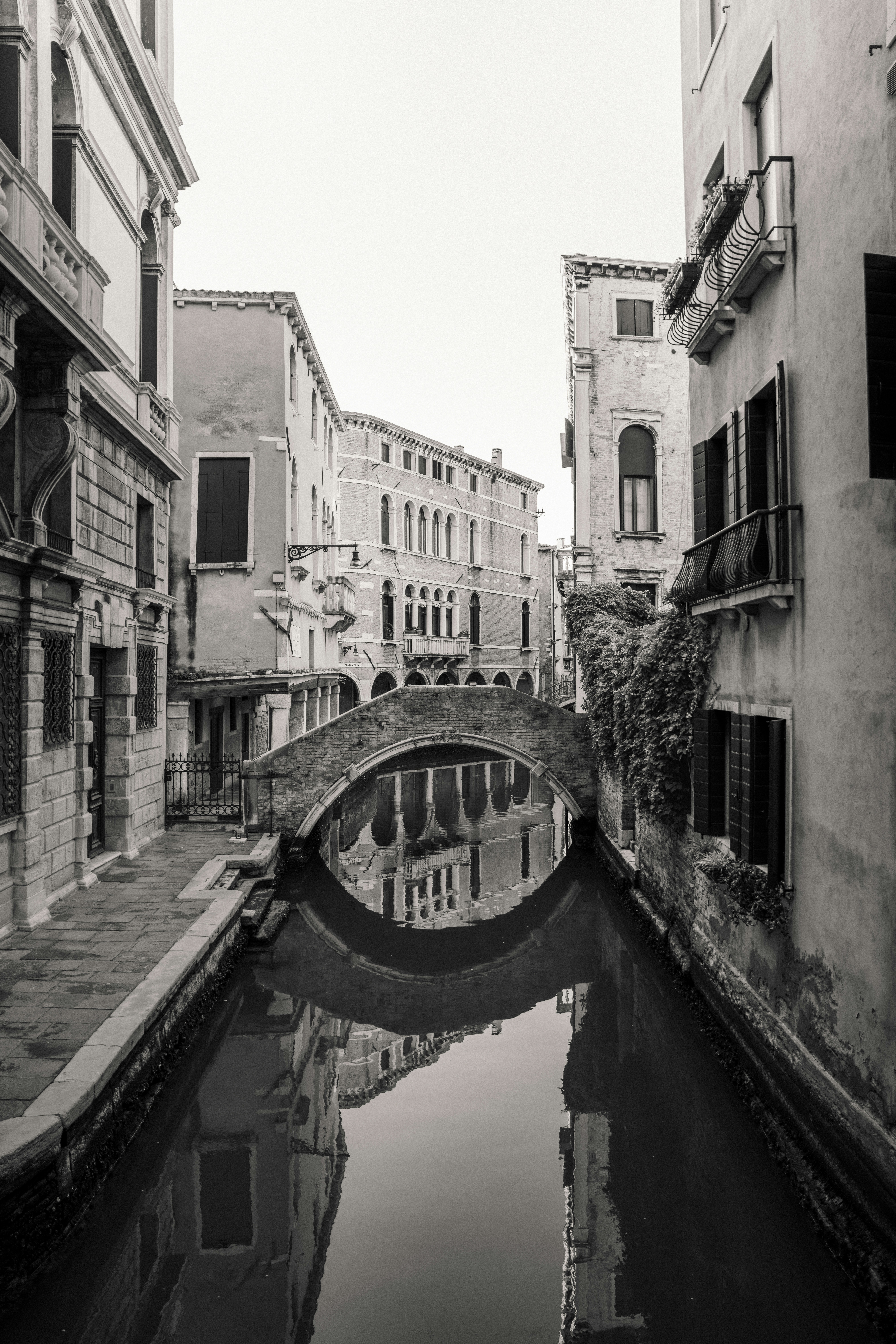 Historic venetian canal with arched bridge and building reflections.