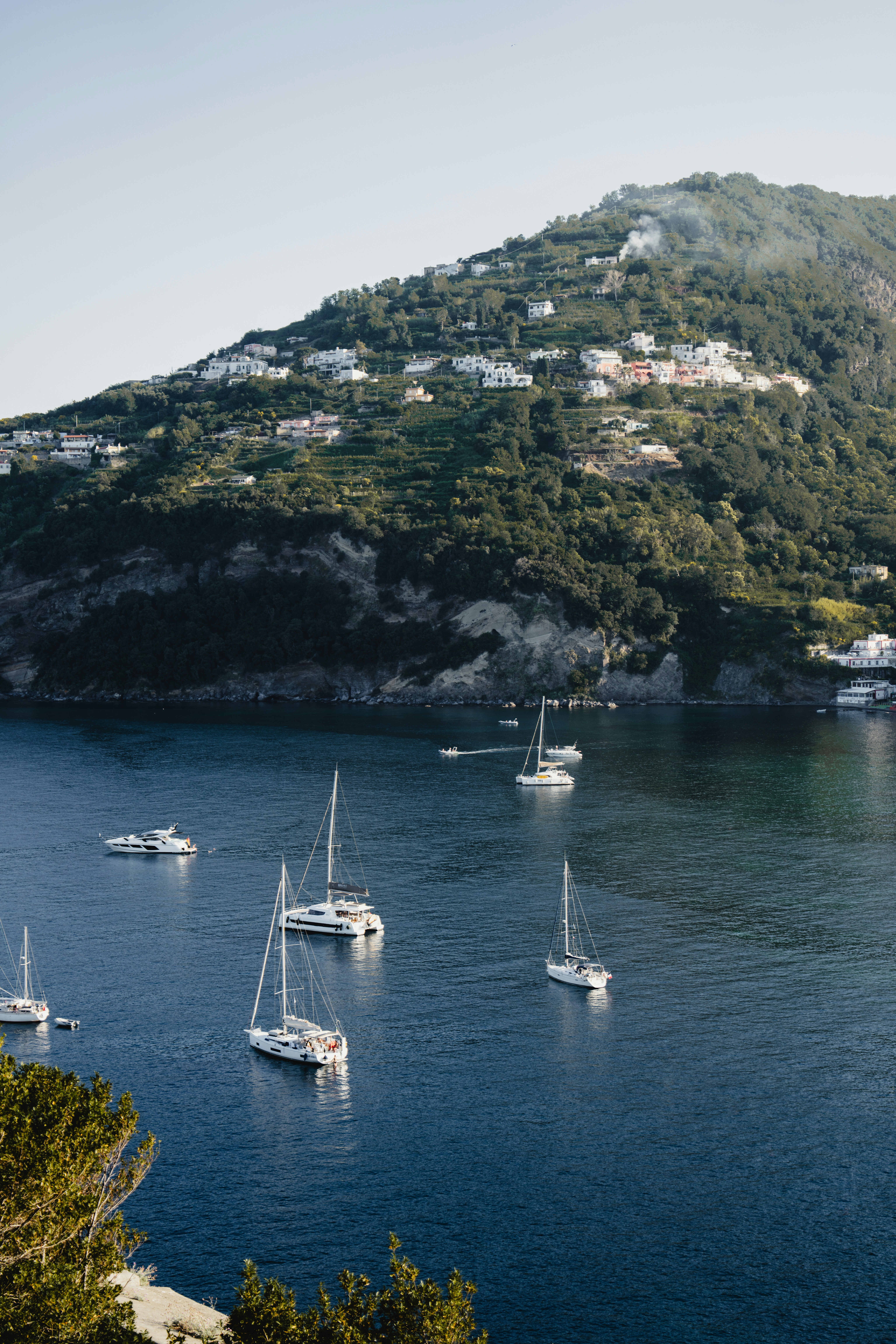 Sailboats in a calm bay with a hillside village.