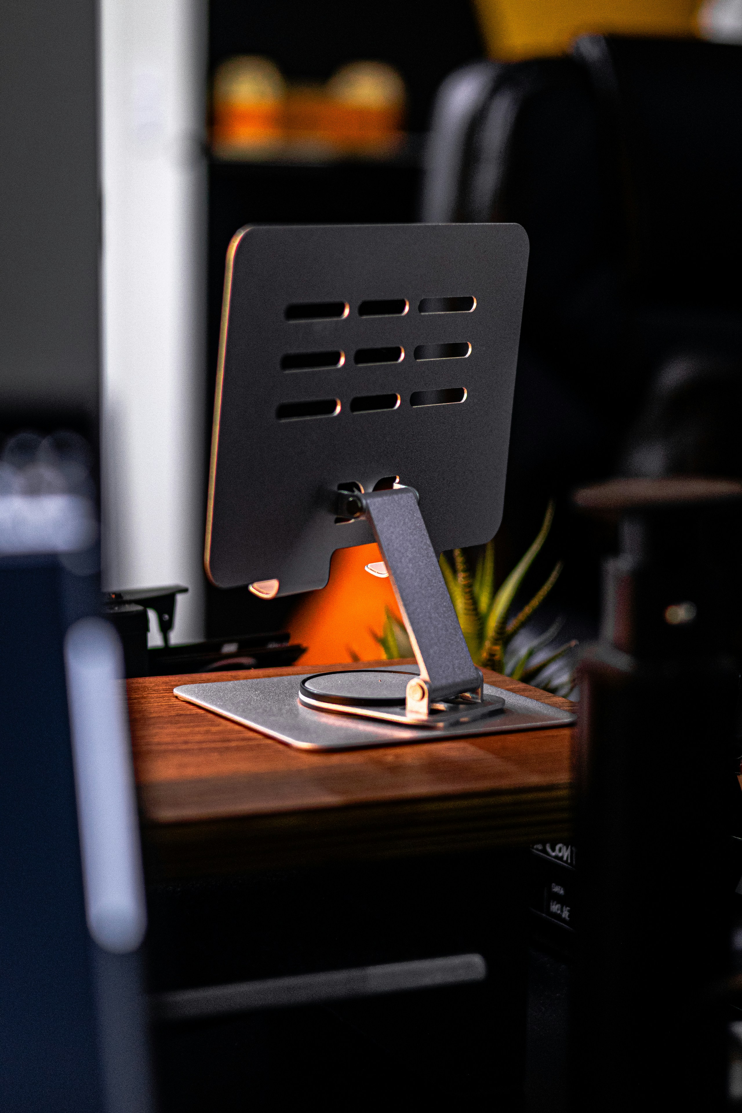 A minimalist tablet stand sits on a wooden desk, suggesting focused work or digital engagement.