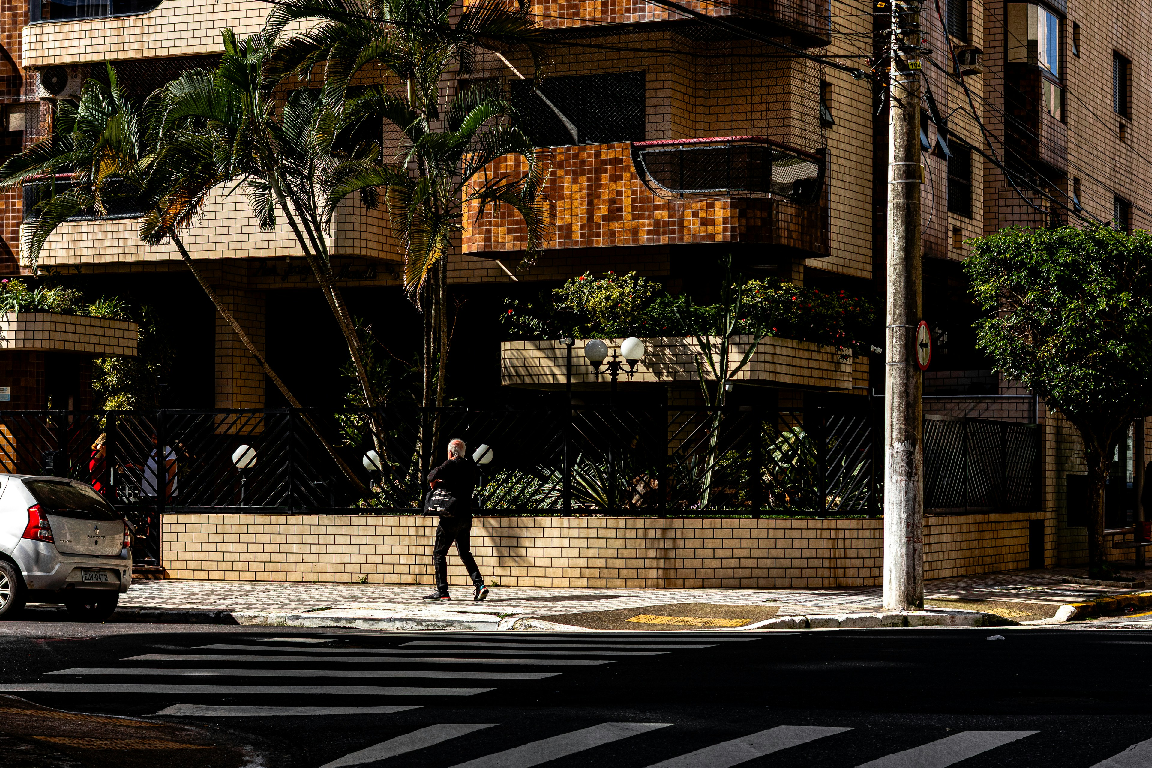 Urban Crossing: A Lone Pedestrian Beneath Brick Facades
