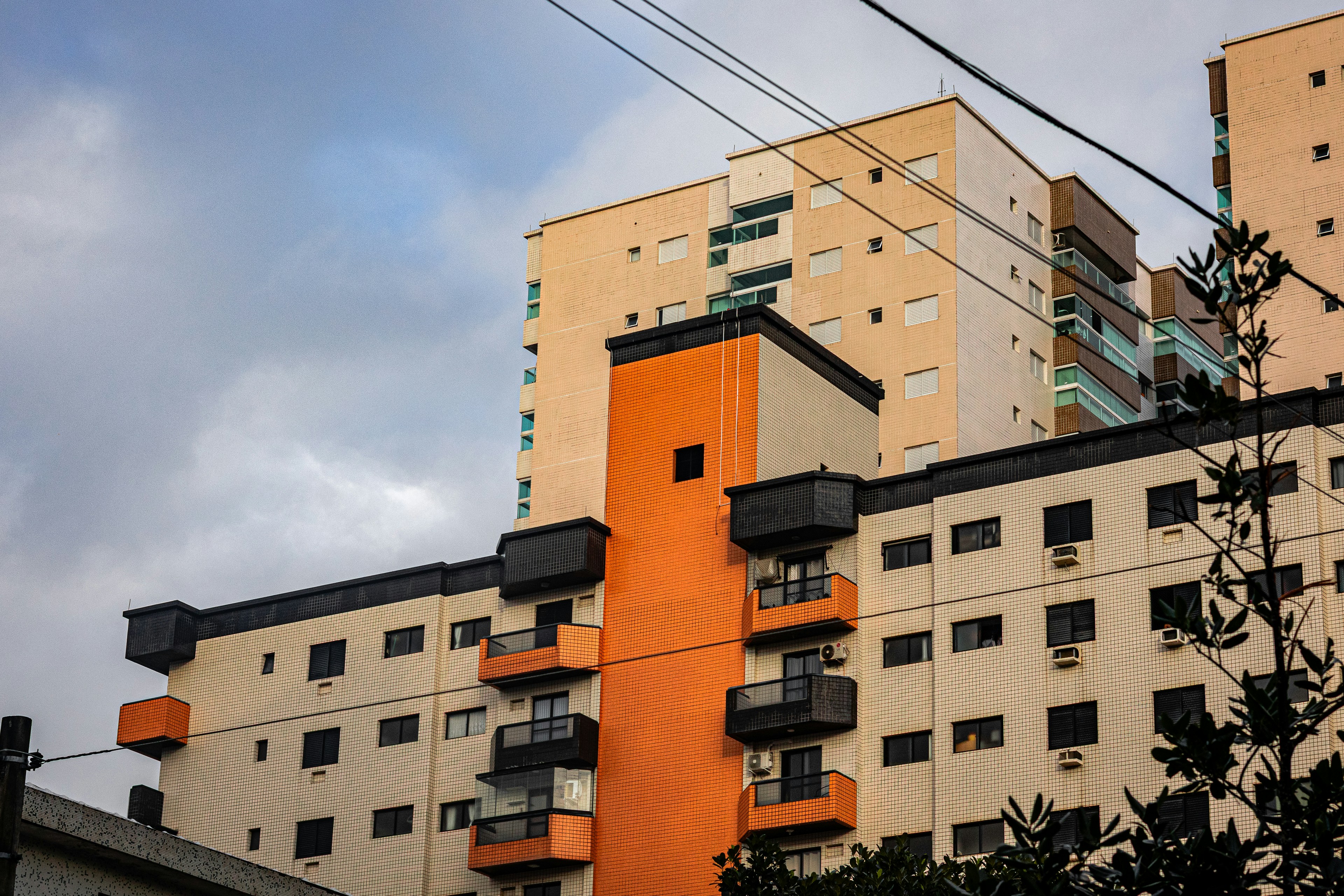 Modern apartment buildings with balconies and windows under a cloudy sky.