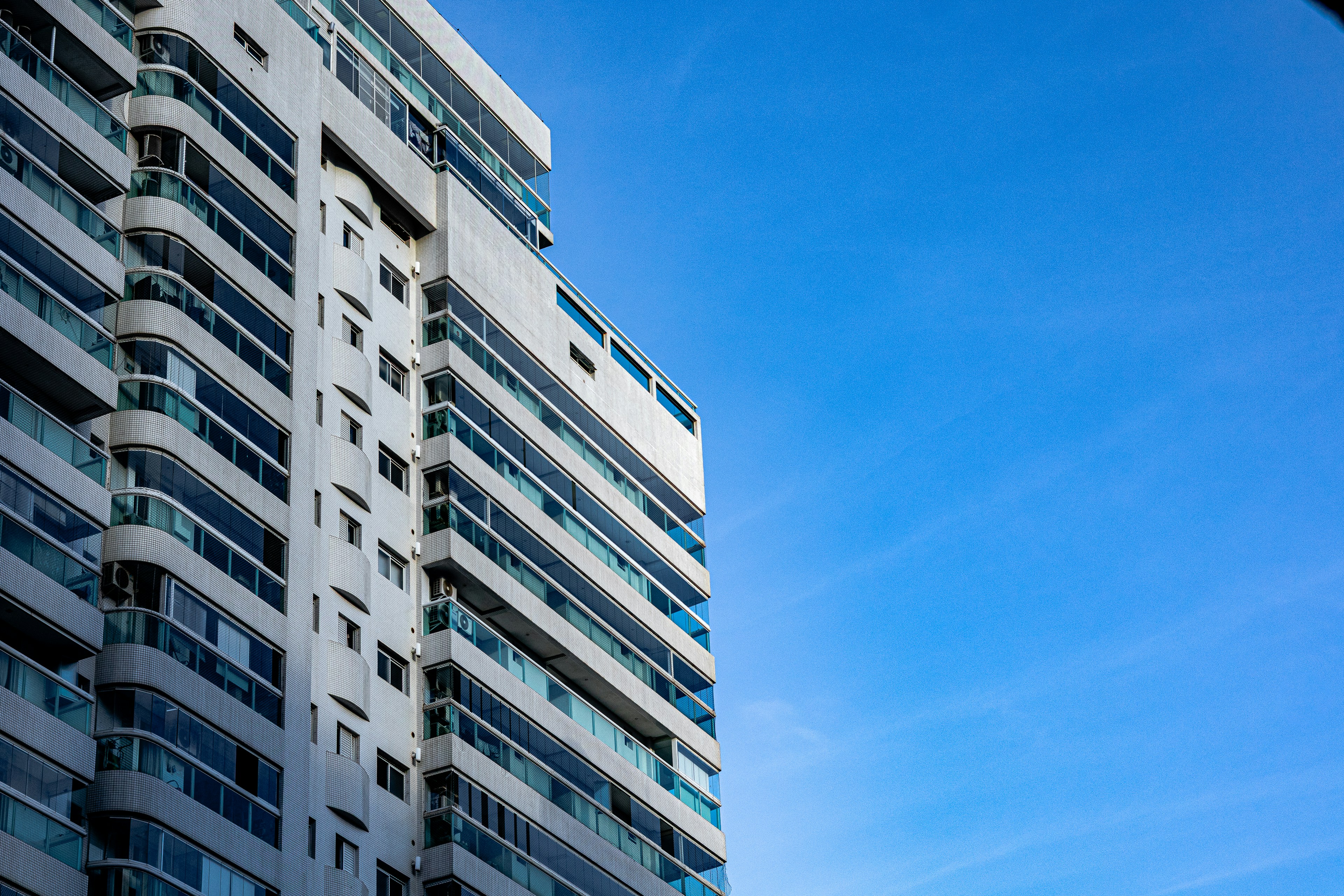 Modern apartment building facade against a clear blue sky, symbolizing urban living and aspiration.