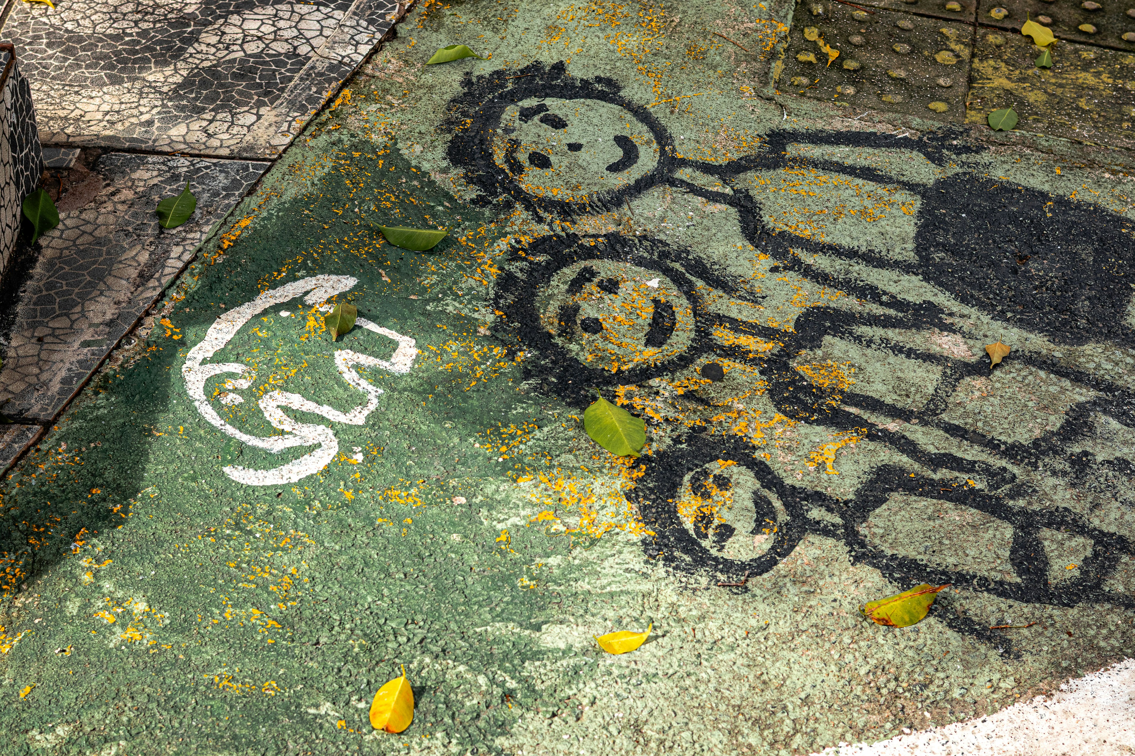Kid-drawn chalk figures on sunlit pavement beside a white logo