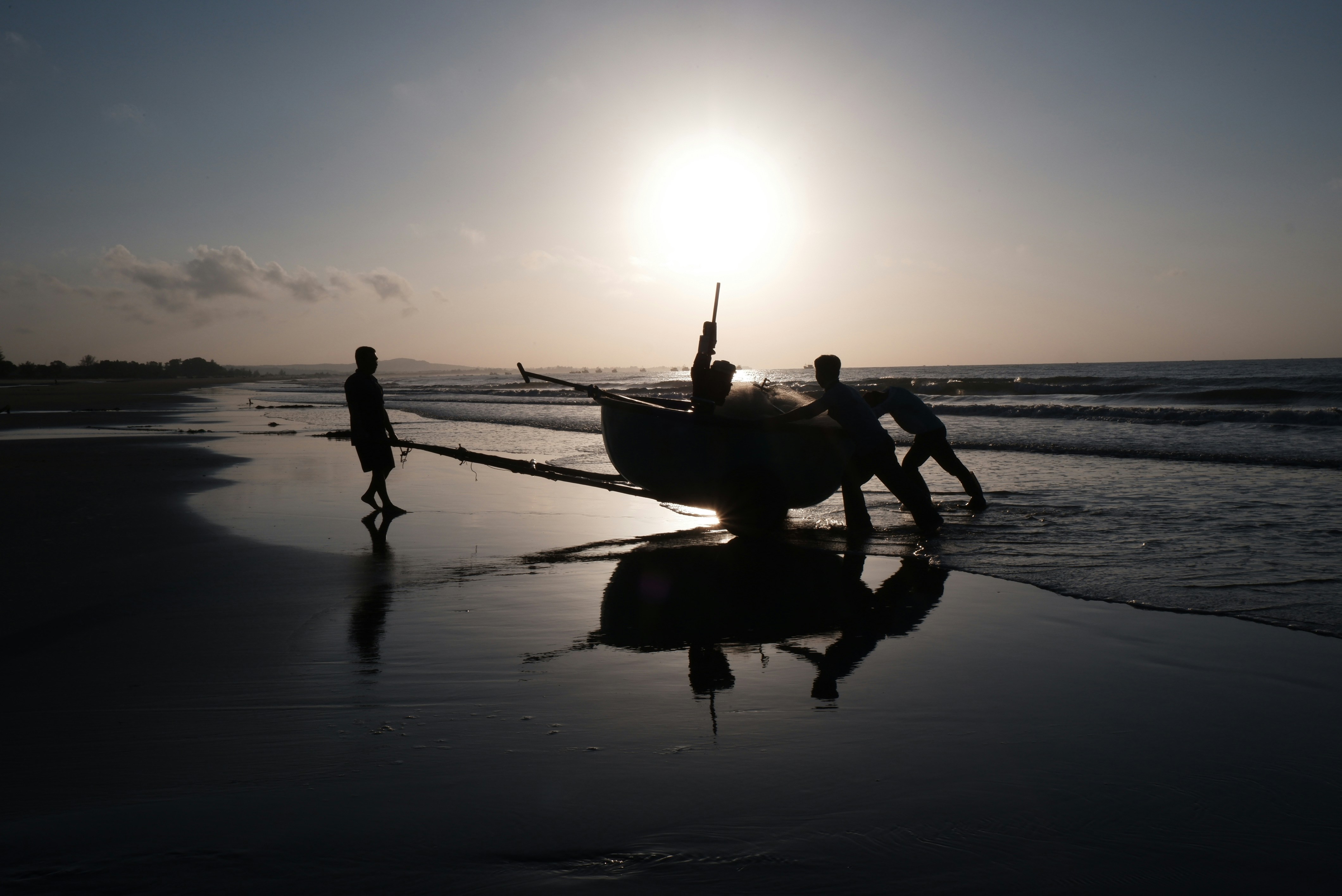Silhouetted Boat and Crew Atop a Dusk-Quiet Tidal Plain