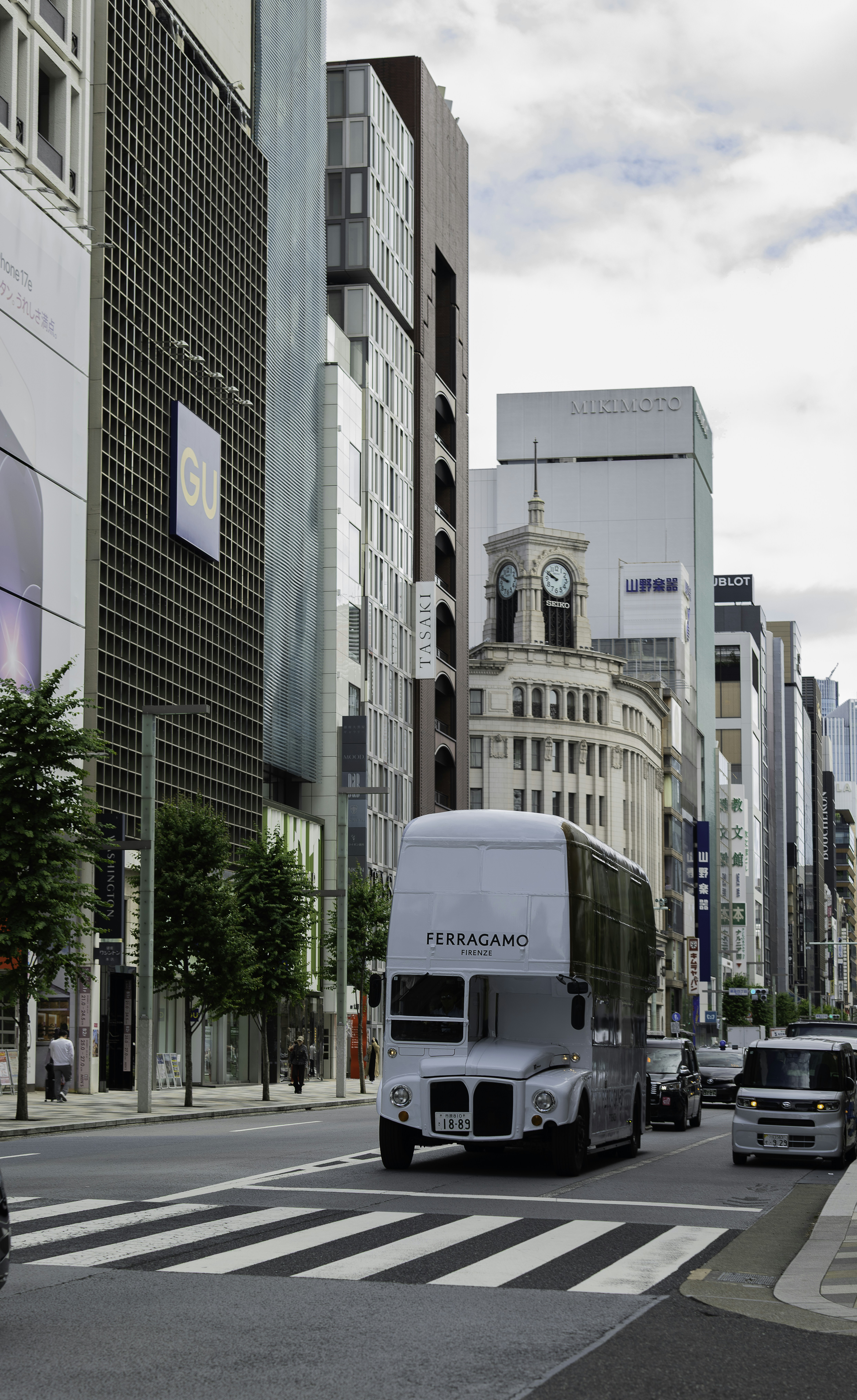 City Transit: A White Ferrargamo Bus Navigates a Skyward Urban Canyon