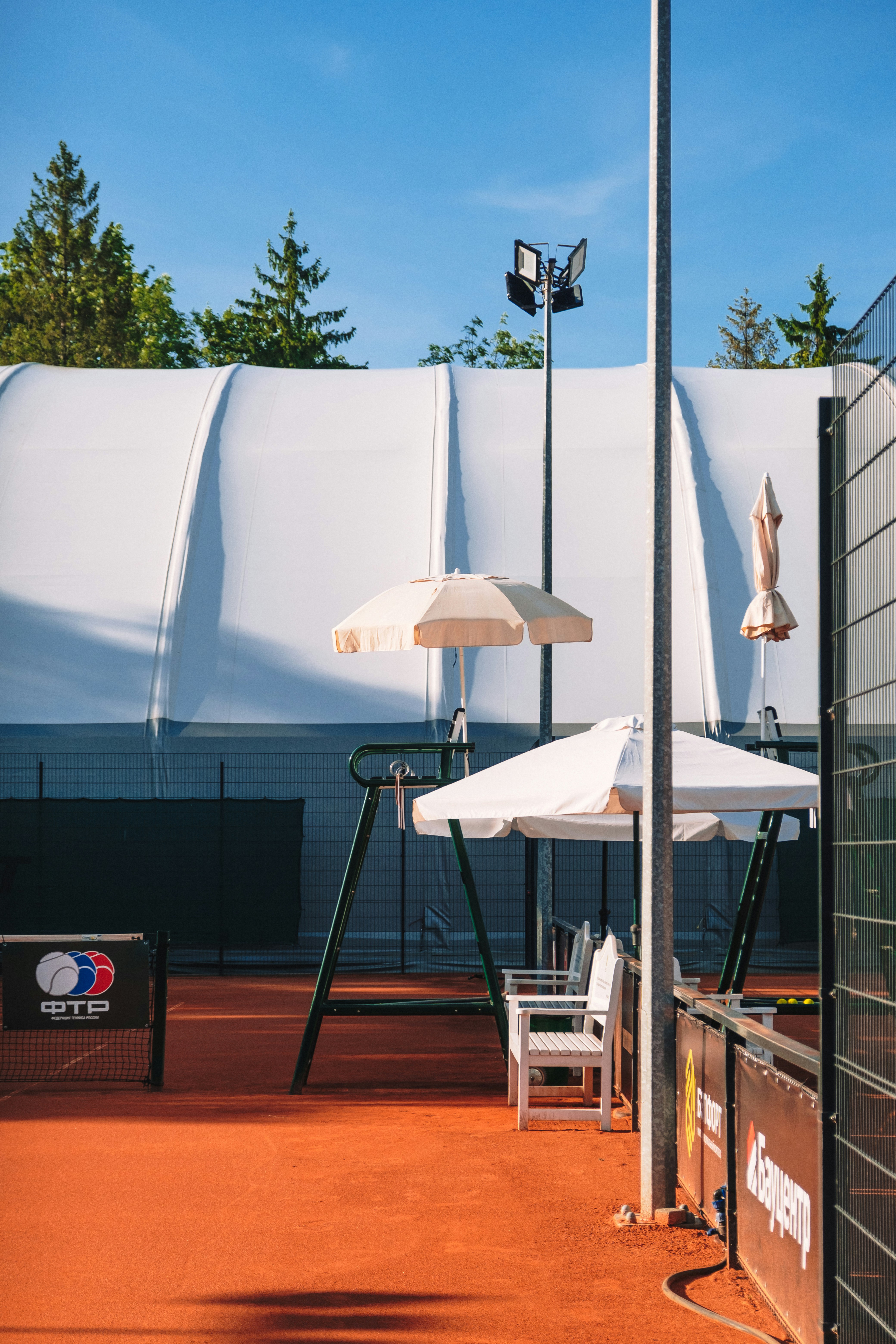 Shade, Net, and Shelter: Quiet Corner of a Tennis Court