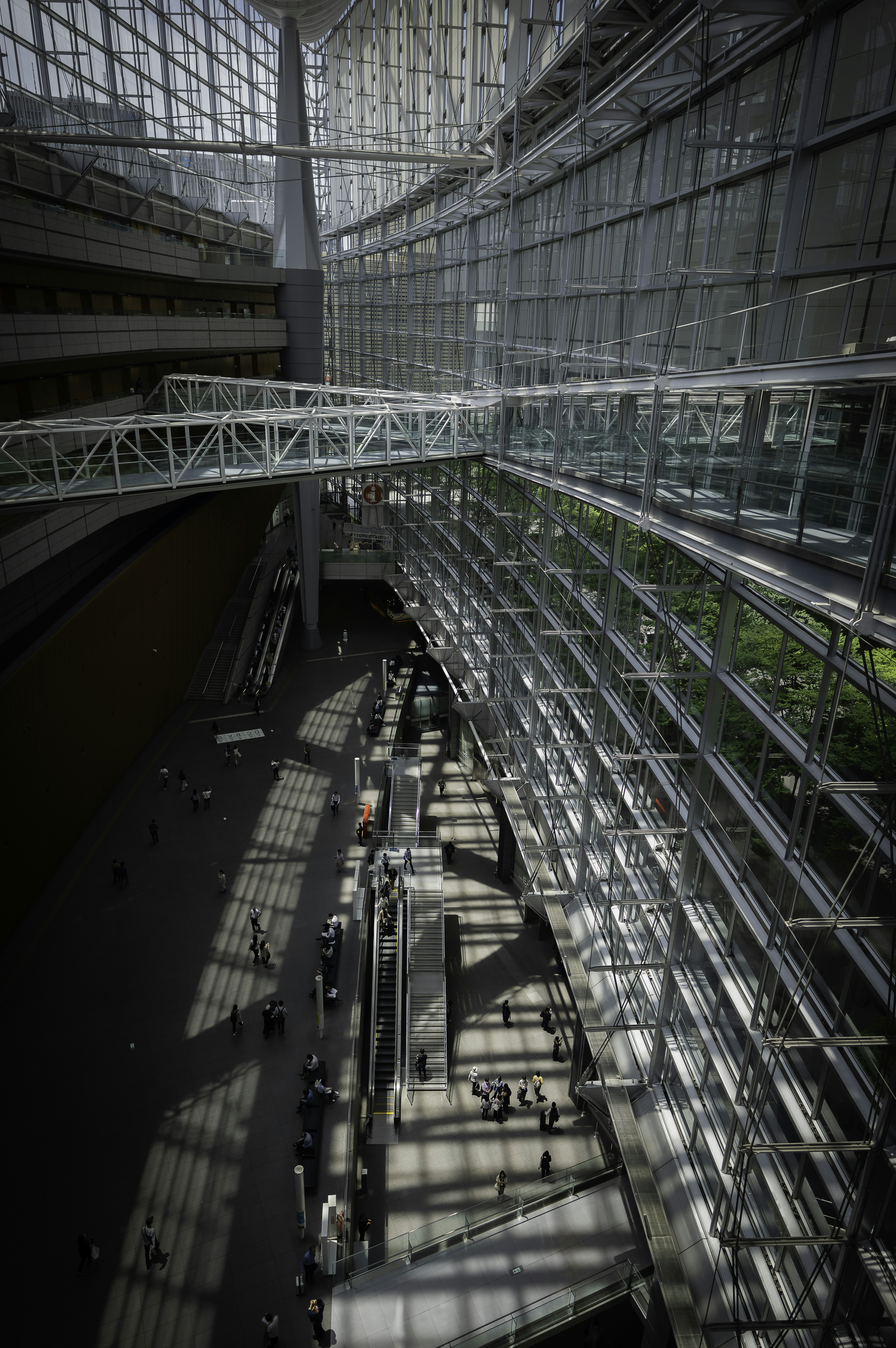 Modern building interior with glass walls, walkways, and people.