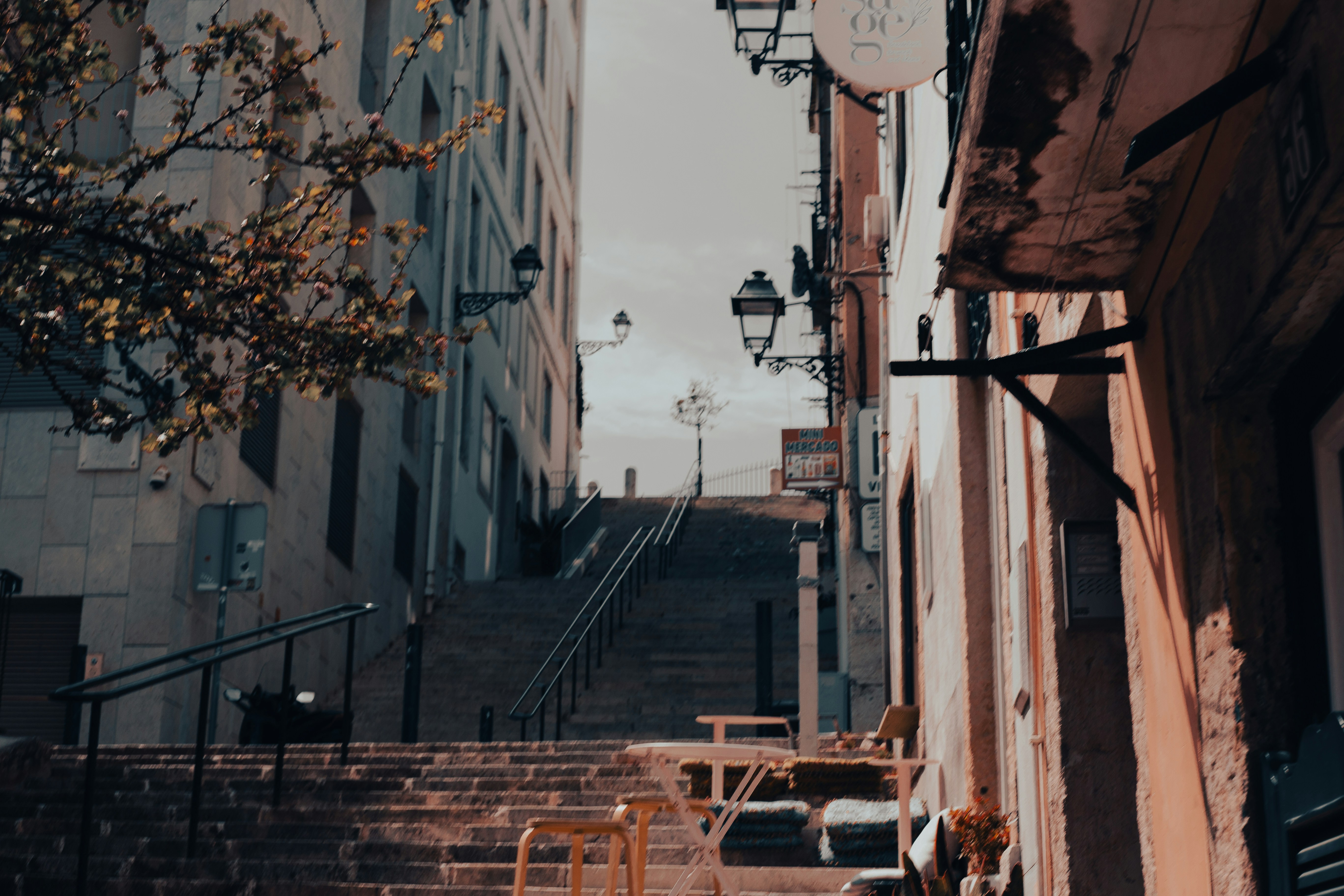 Urban stairs toward a sunlit street between brick buildings