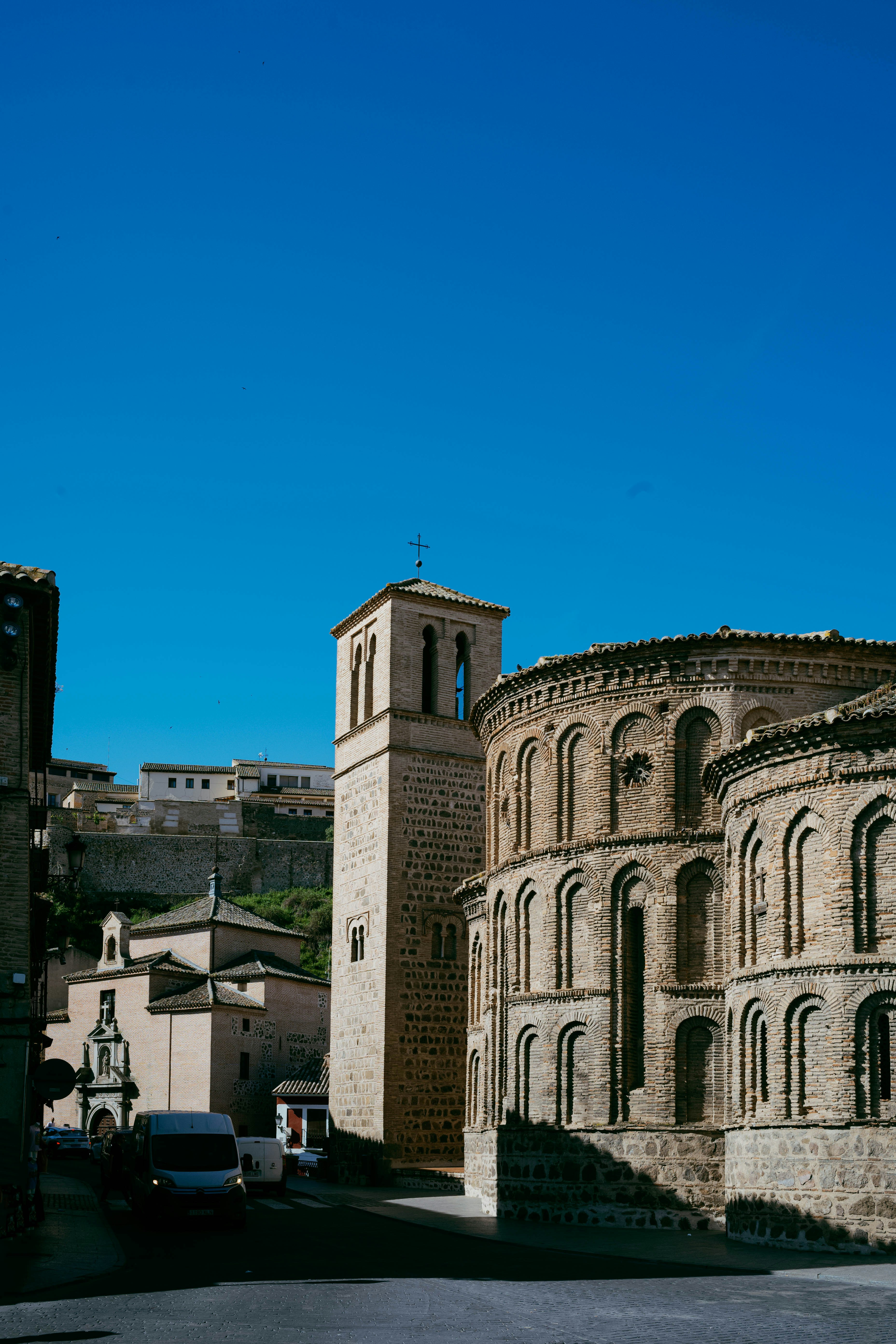 Historic stone bell tower and church building under blue sky.