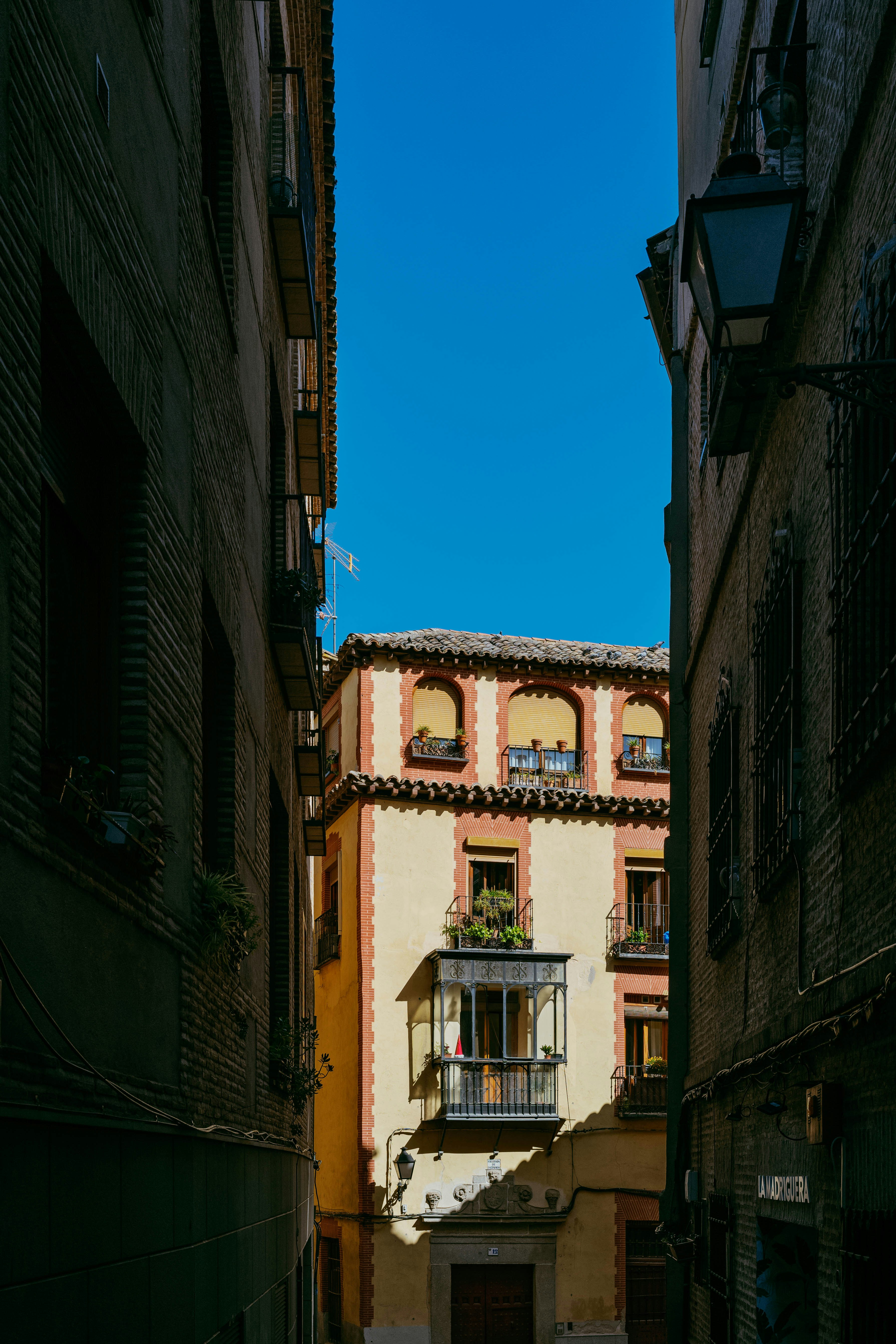Old building with balcony visible through narrow alleyway.