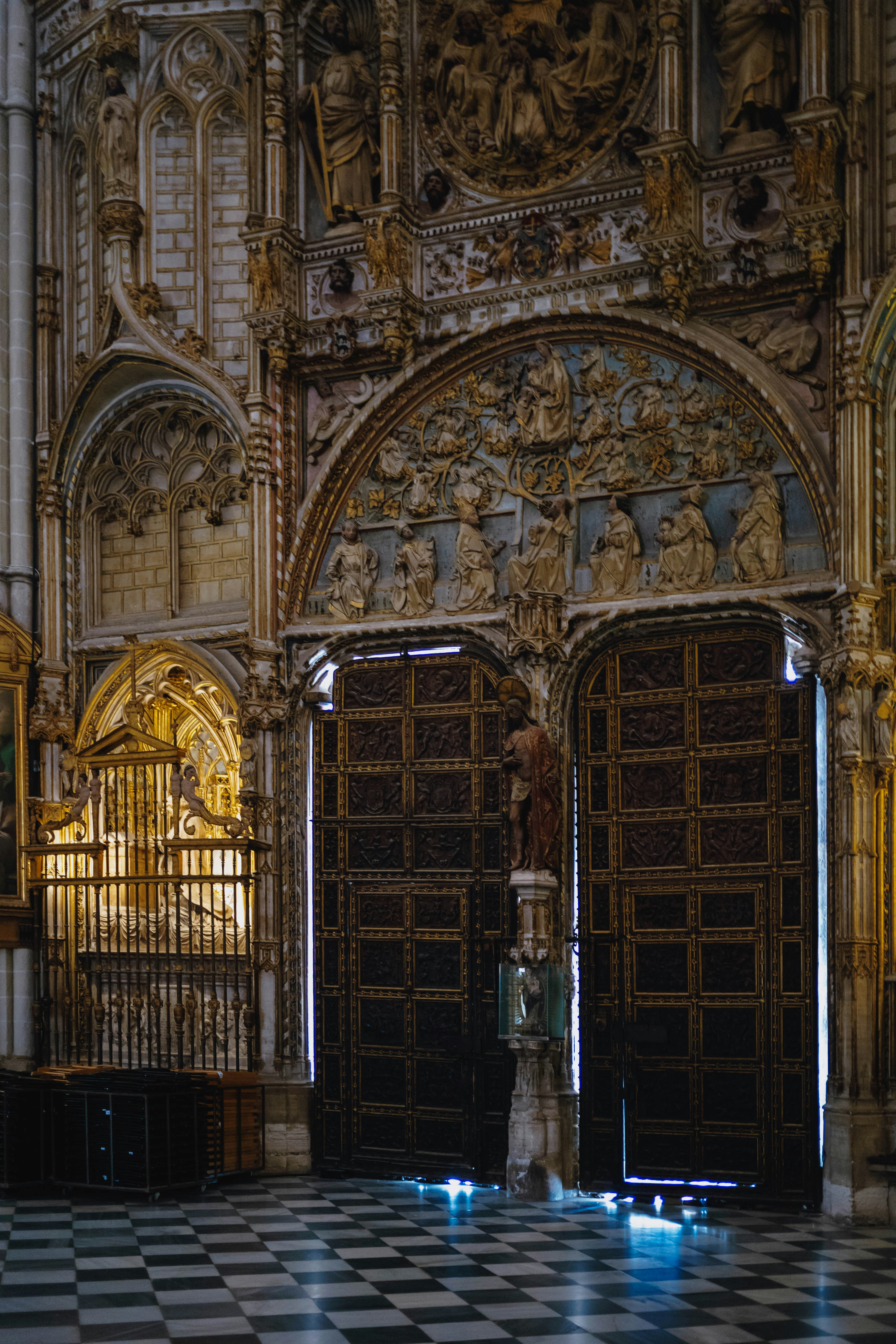 Intricate gothic cathedral interior with carved doors and checkered floor.
