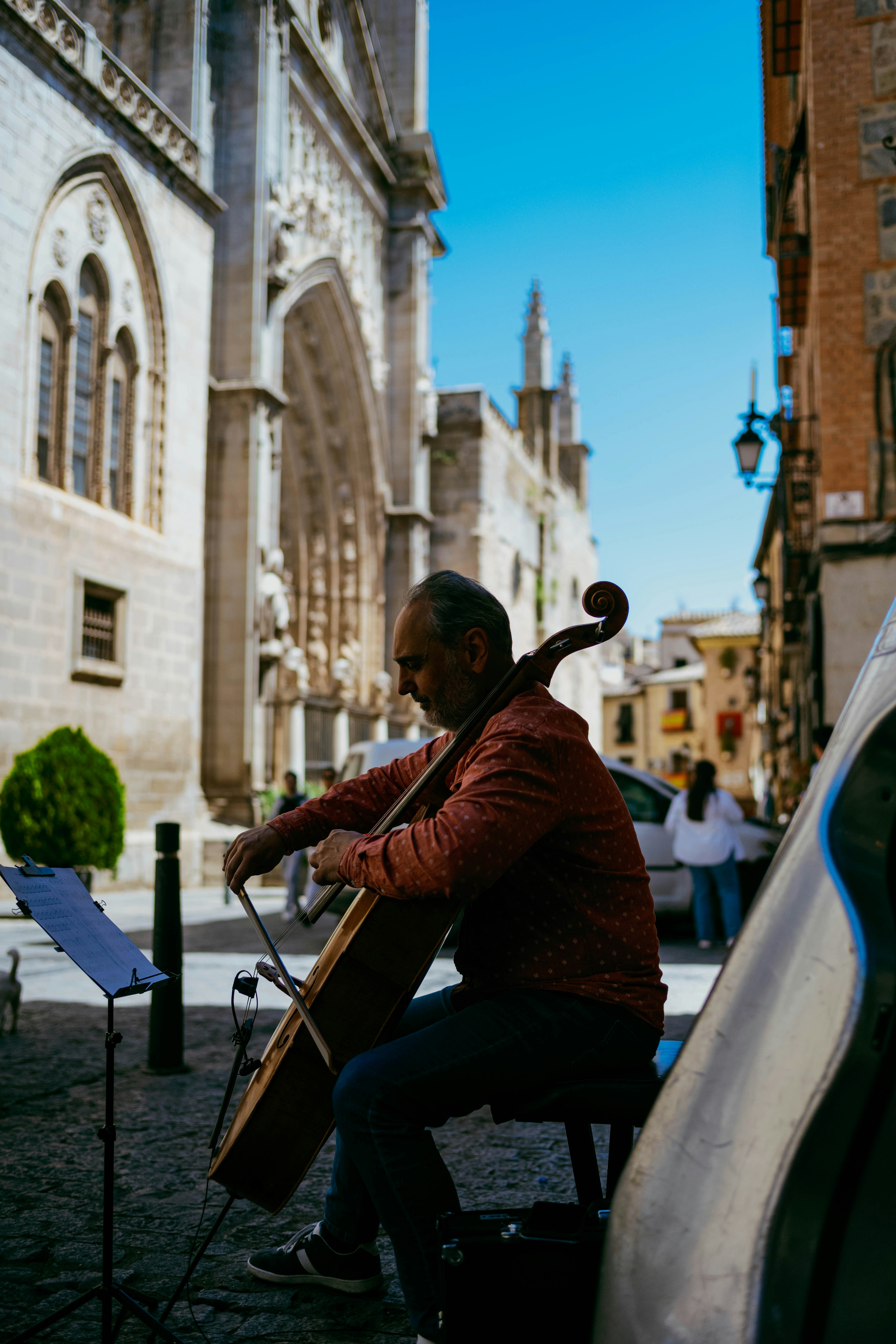 Musician playing cello on a historic city street.