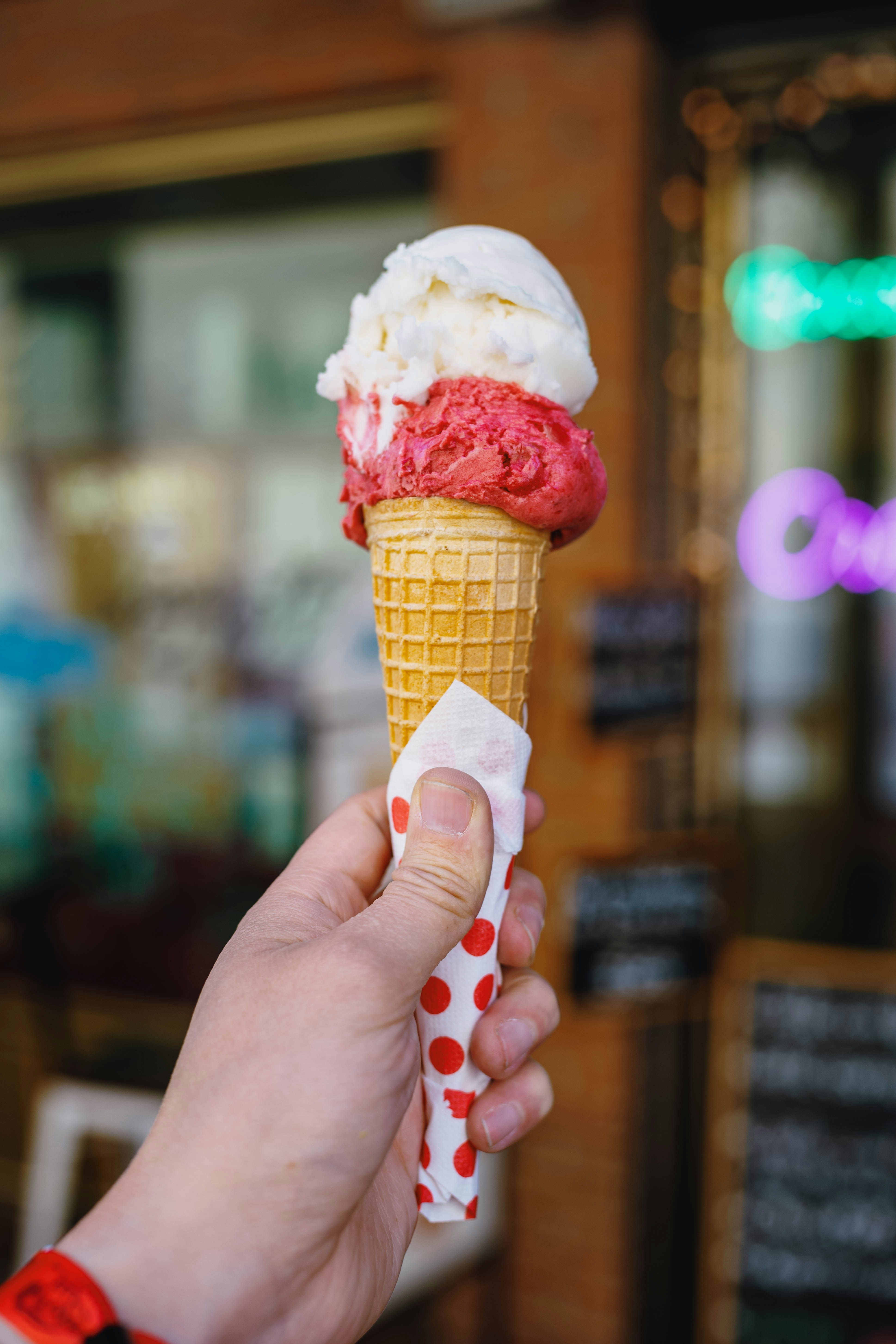 Hand holding a two-scoop ice cream cone.