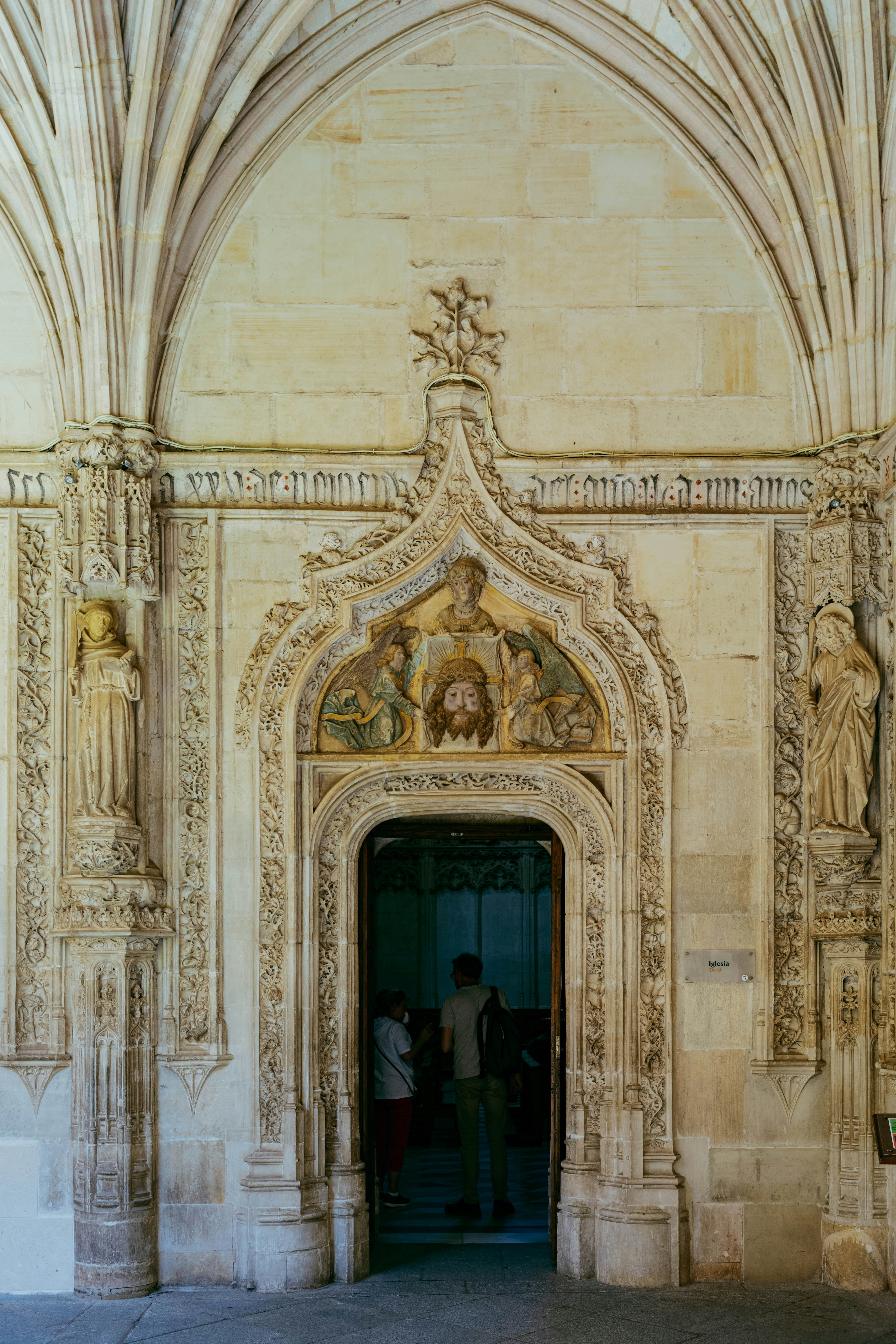 Intricate stone doorway with statues and vaulted ceiling.
