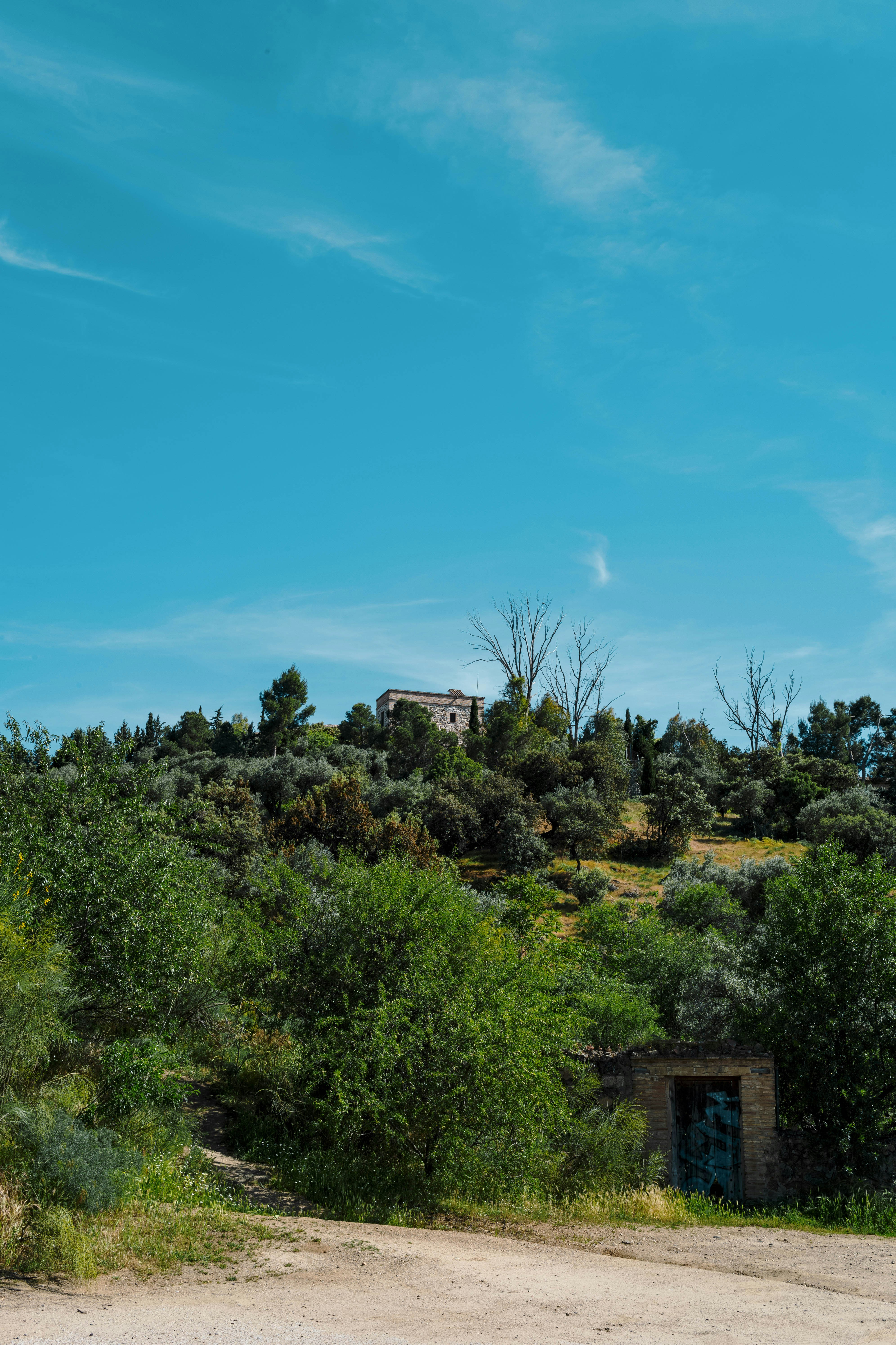 Stone building on a green hillside under a blue sky.