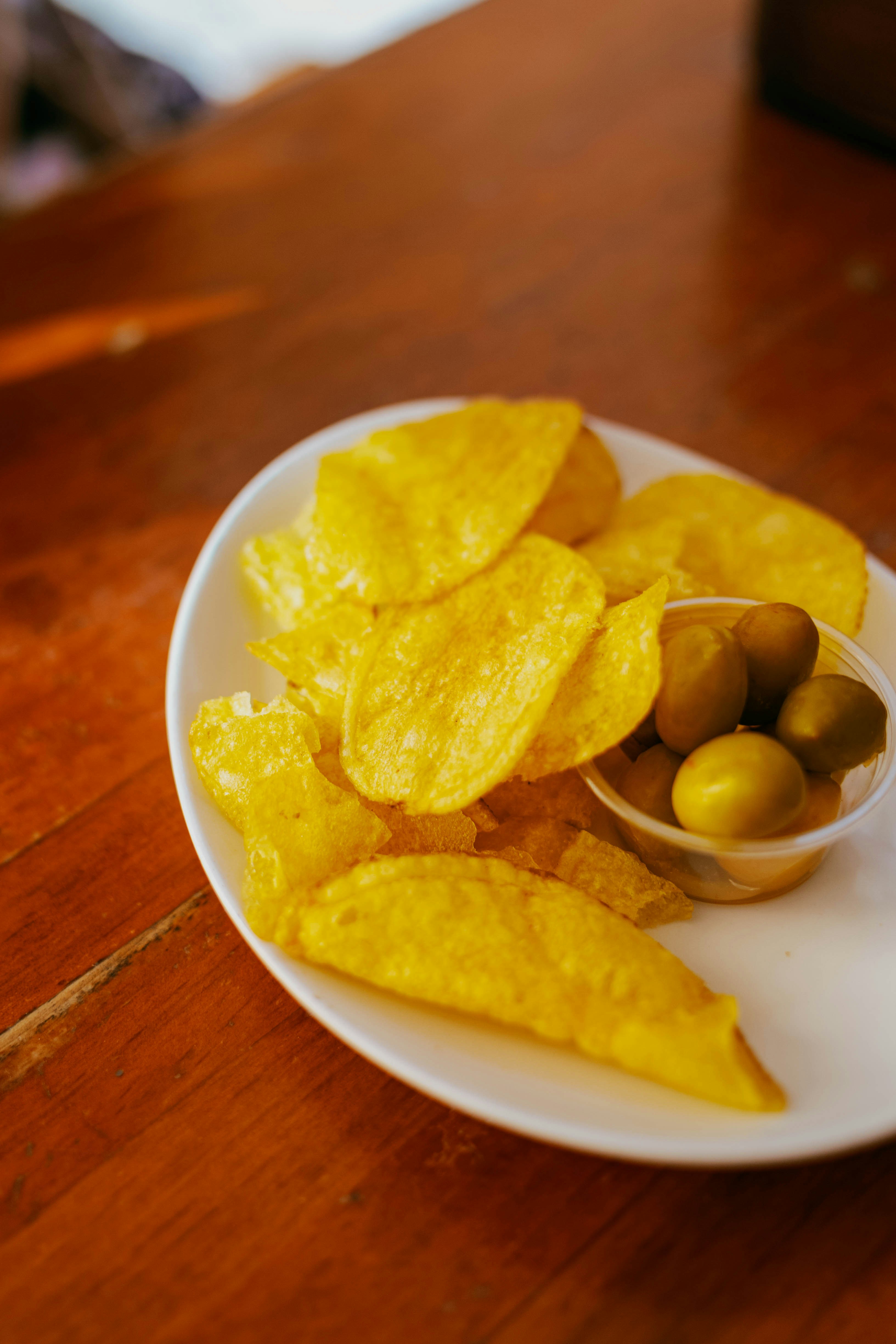 Golden Crunch on a Wooden Stage: Chips and Olives as Afternoon Snack